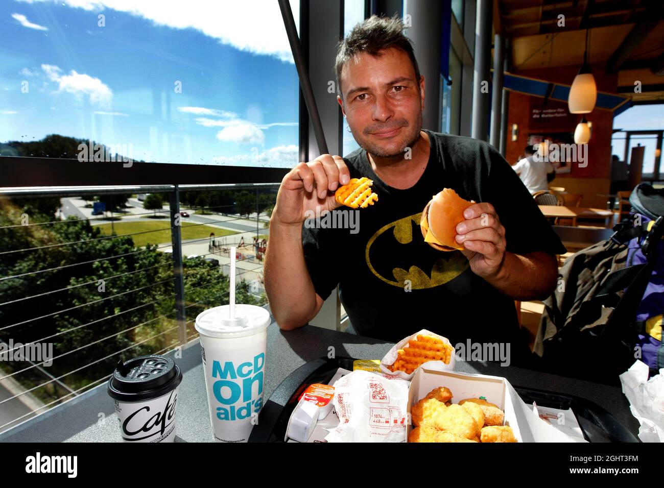 Man eats hamburger, McDonalds restaurant, fast food, bridge restaurant ...