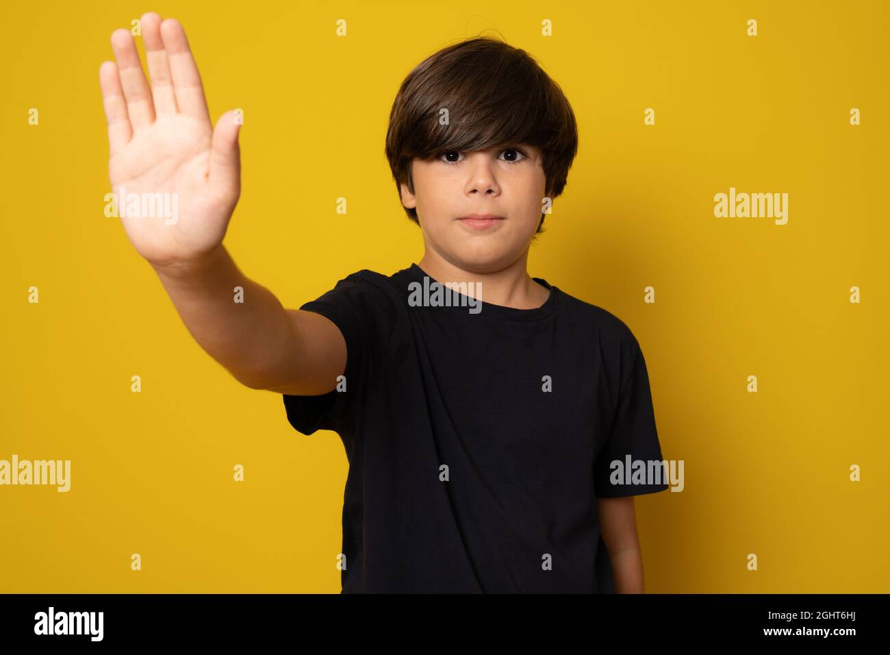 Child looking at camera. Stop signal with his hand over yellow ...