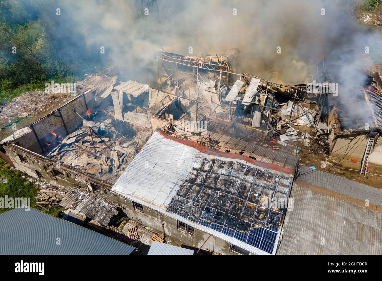 Aerial view of ruined building on fire with collapsed roof and rising ...