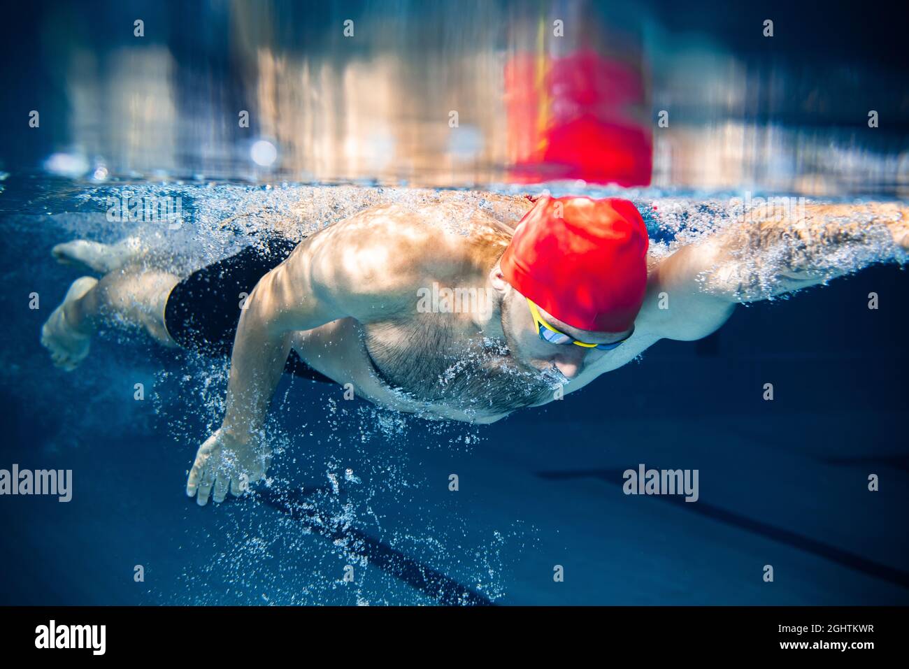 Underwater view of professional male swimmer in red cap and goggles in ...