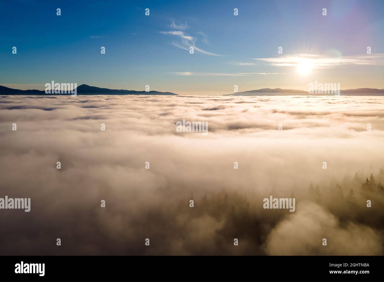 Aerial view of vibrant sunset over white dense clouds with dark ...