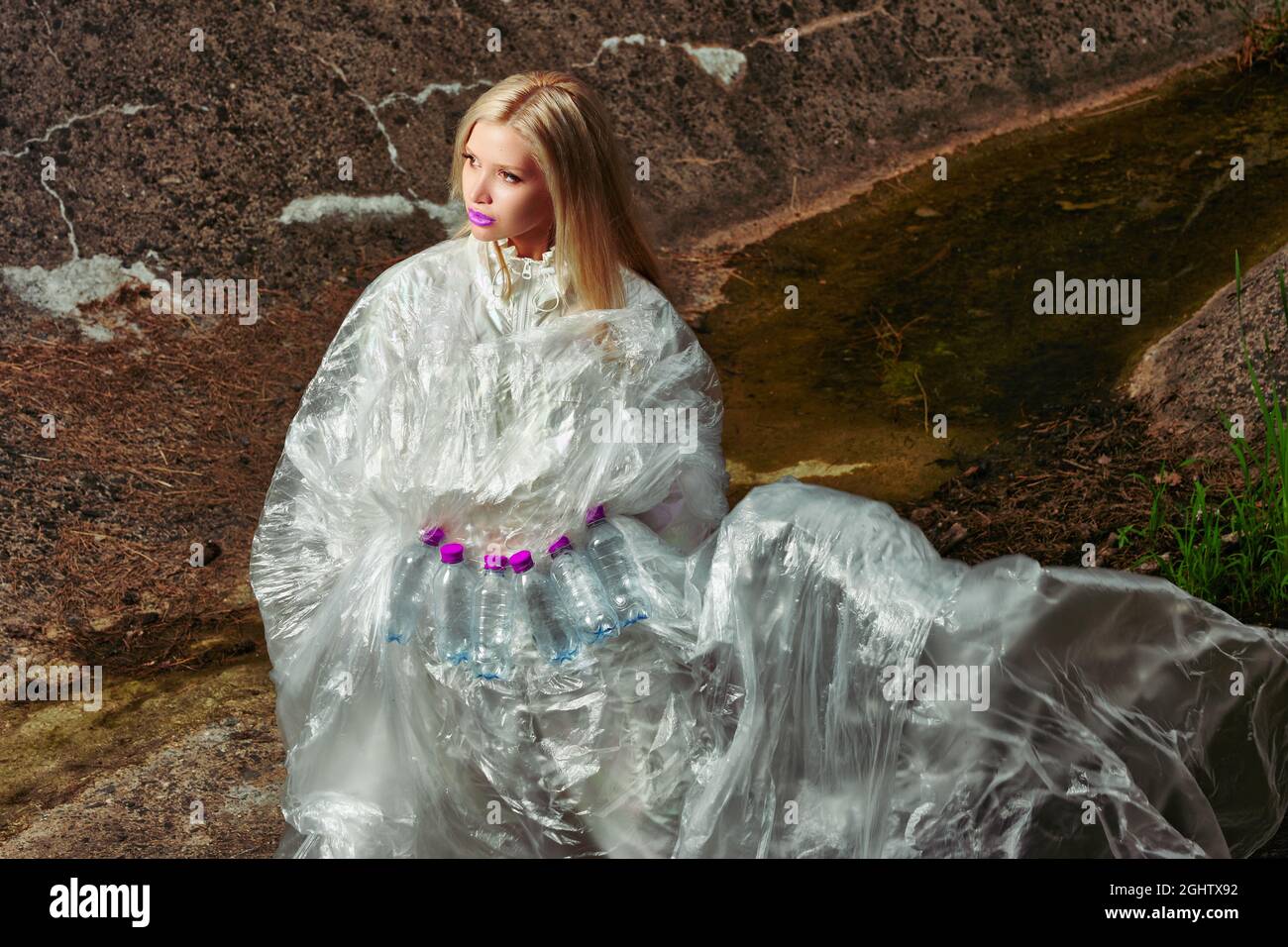 fashion creative. model posing in cellophane with plastic bottles ...