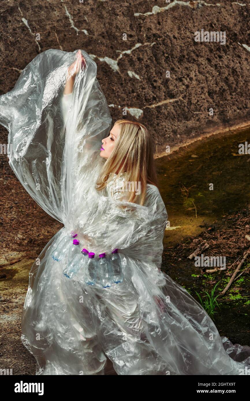 fashion creative. model posing in cellophane with plastic bottles ...