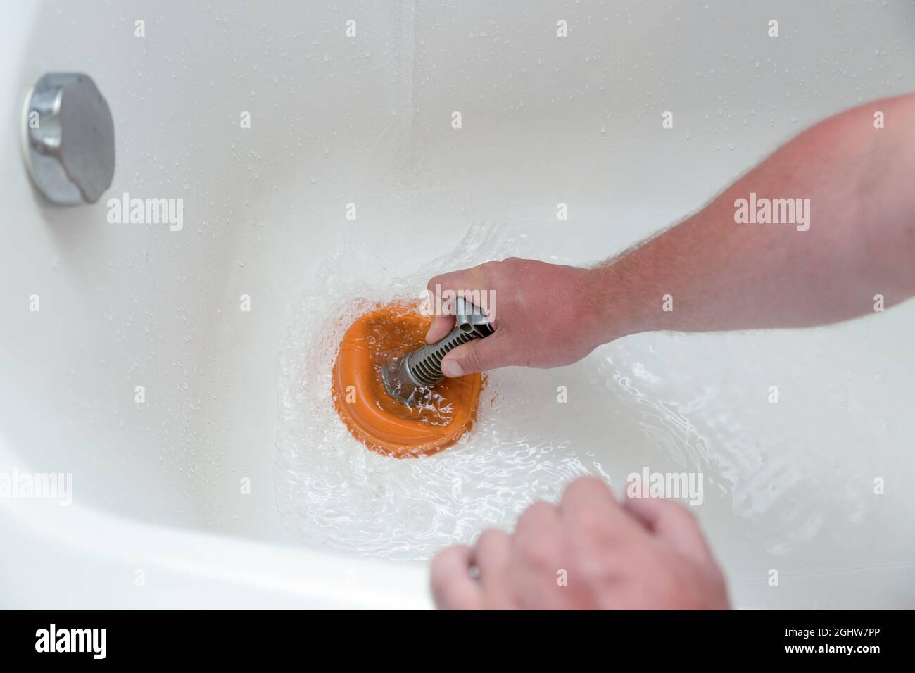 A man's hand with plunger in the bath Cleaning pipes from blockages ...