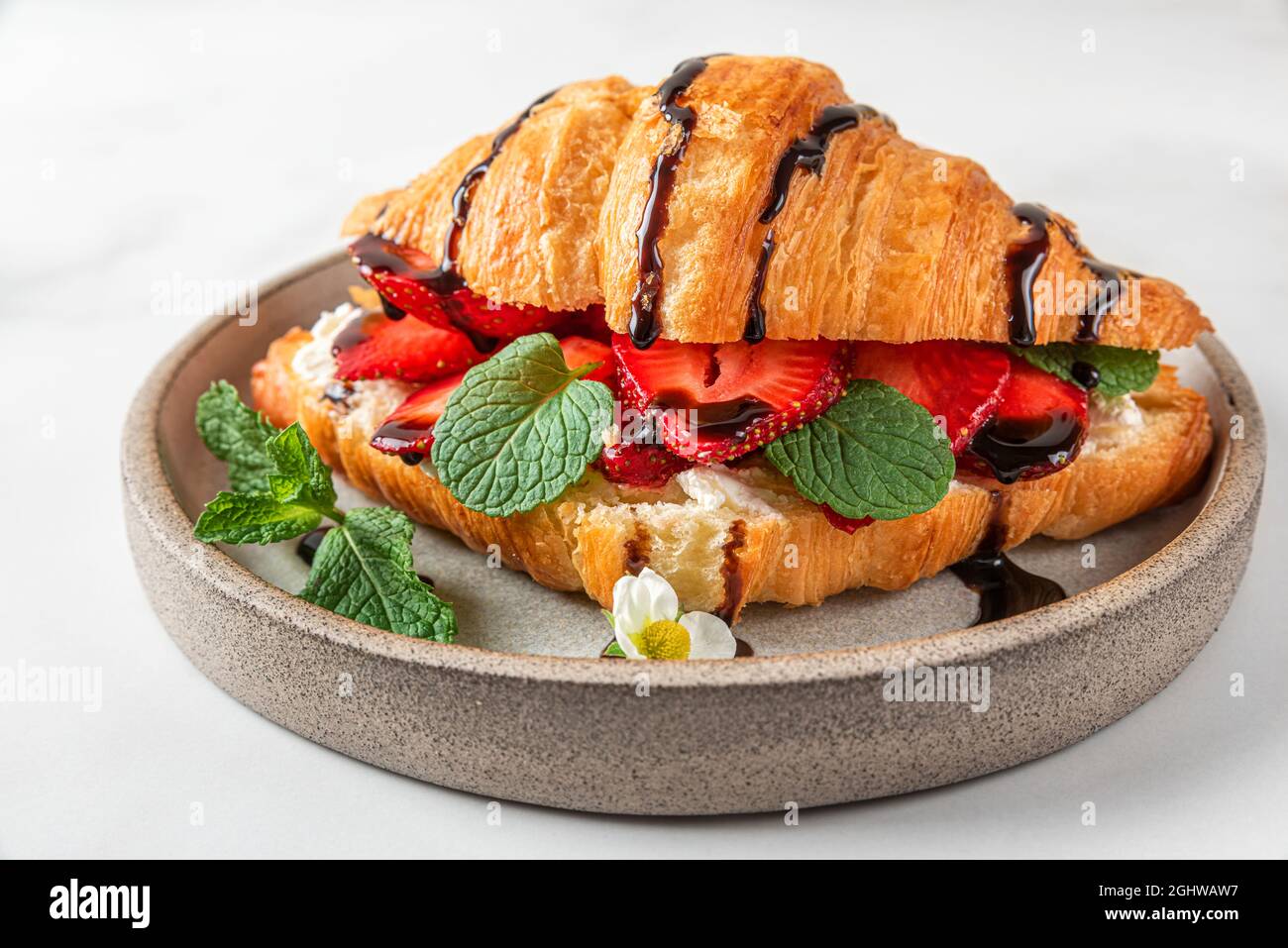 French croissant sandwich with fresh strawberries, cream cheese, mint ...