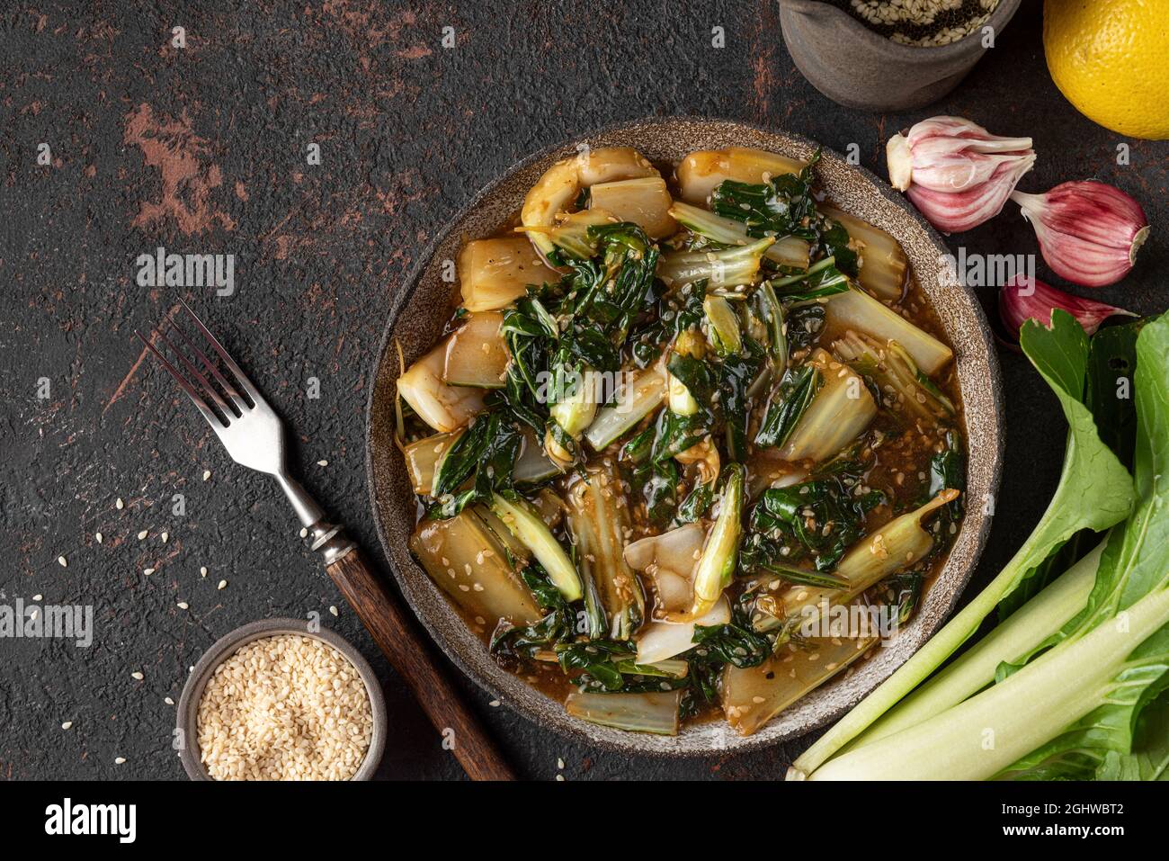Bok choy vegetables stir fry with soy sauce and sesame seeds on dark ...