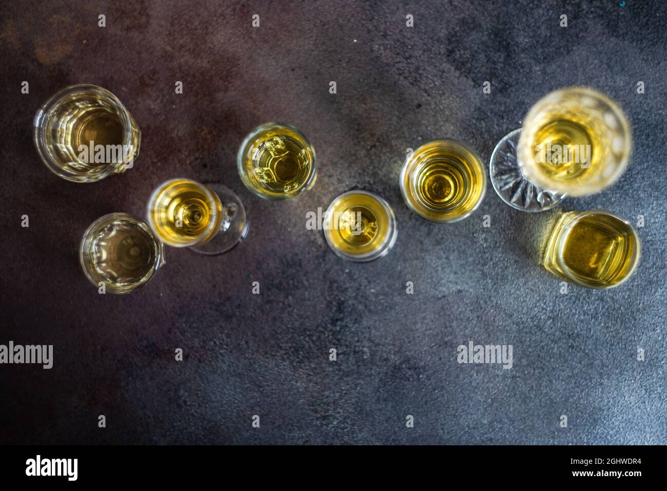 Row of assorted shot glasses, wine glasses and tumblers filled with ...