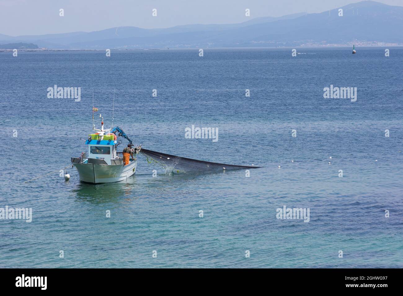 Fishing boat, collecting nets full of fish. fishing near the coast ...