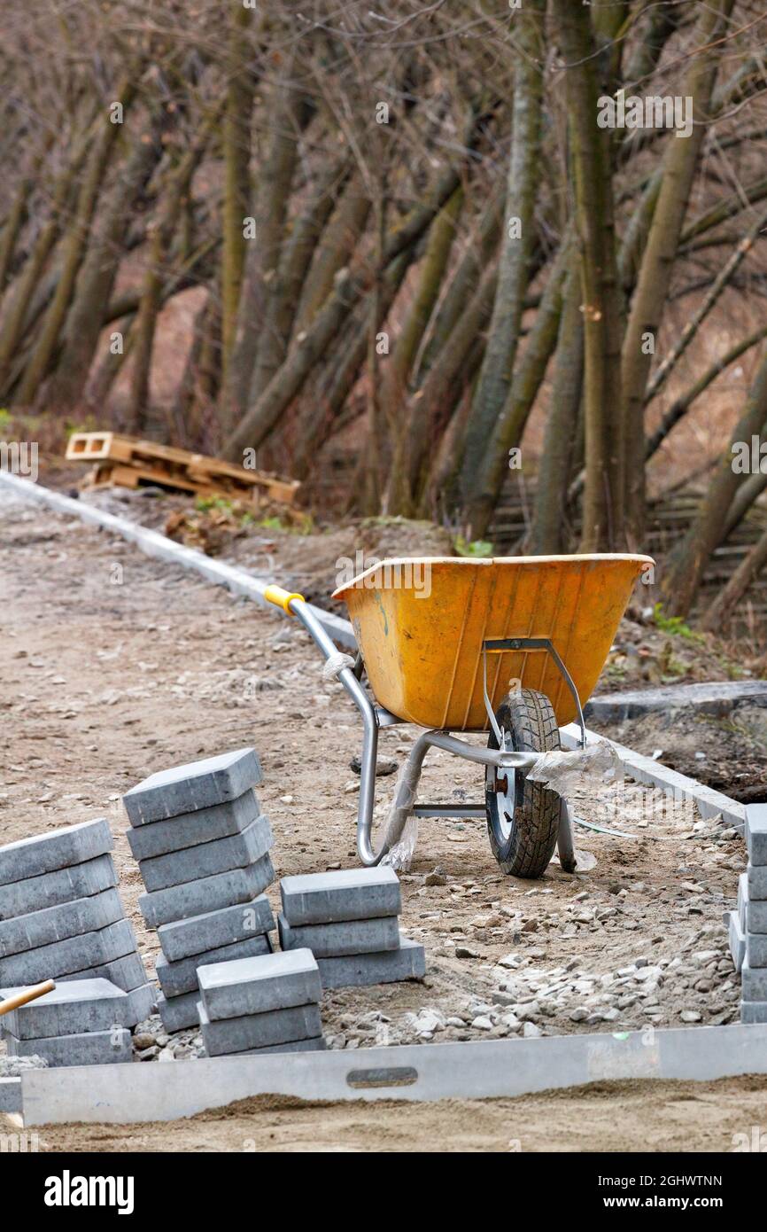 Old yellow construction wheelbarrow against the background of a stack ...