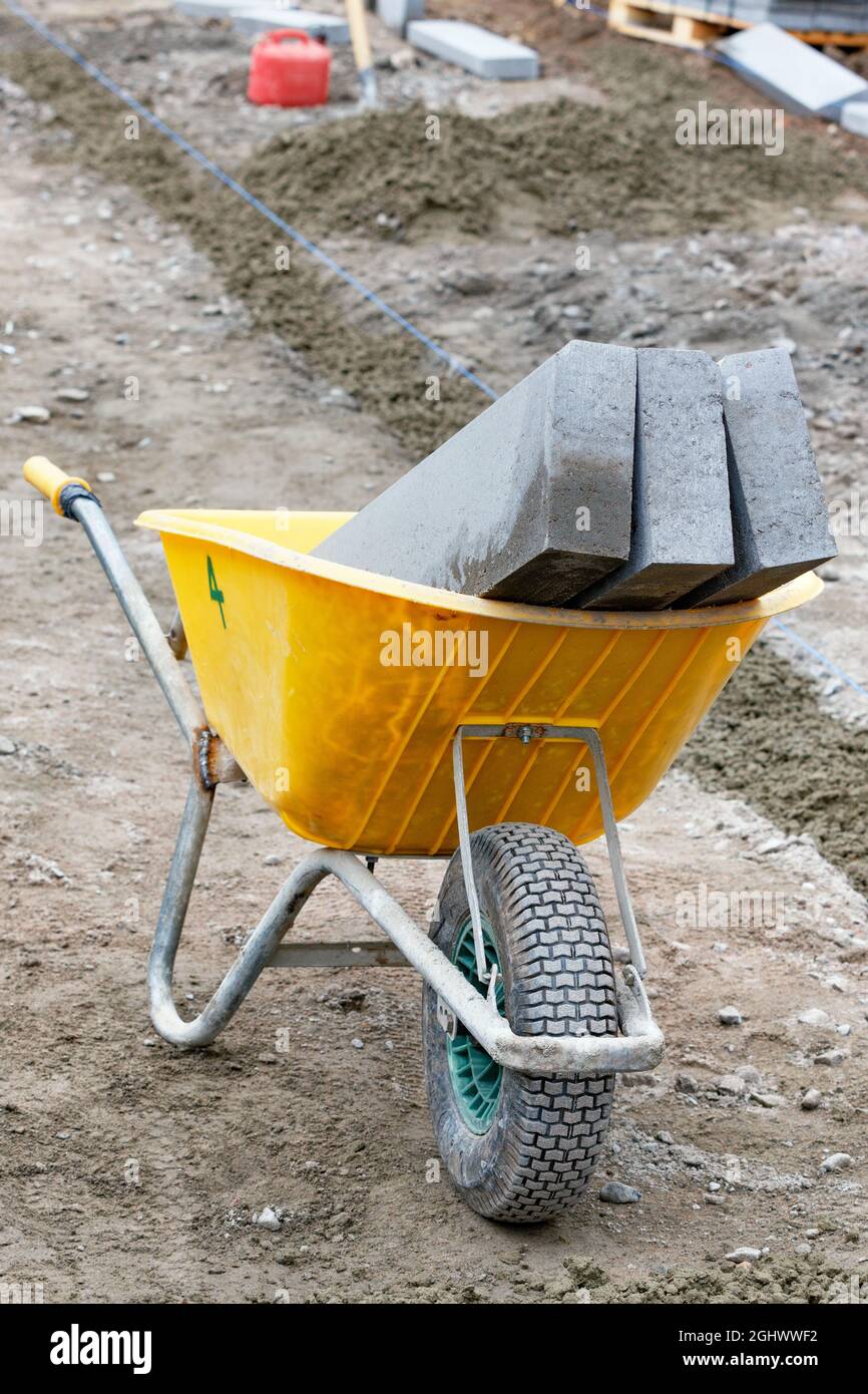 Construction wheelbarrow with loaded concrete roadside blocks at a ...