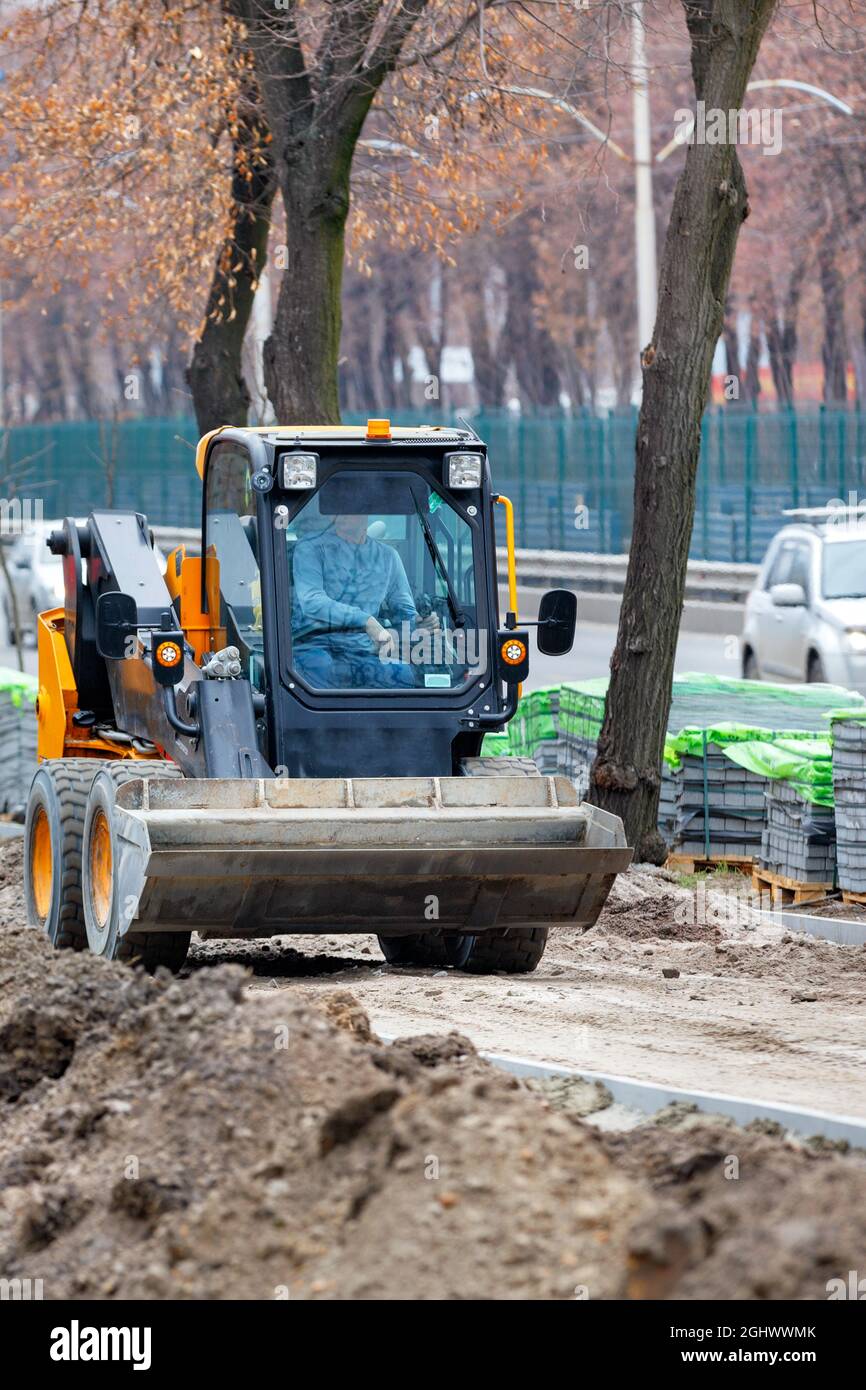 The compact road grader levels sandy soil ahead of the upcoming paving ...