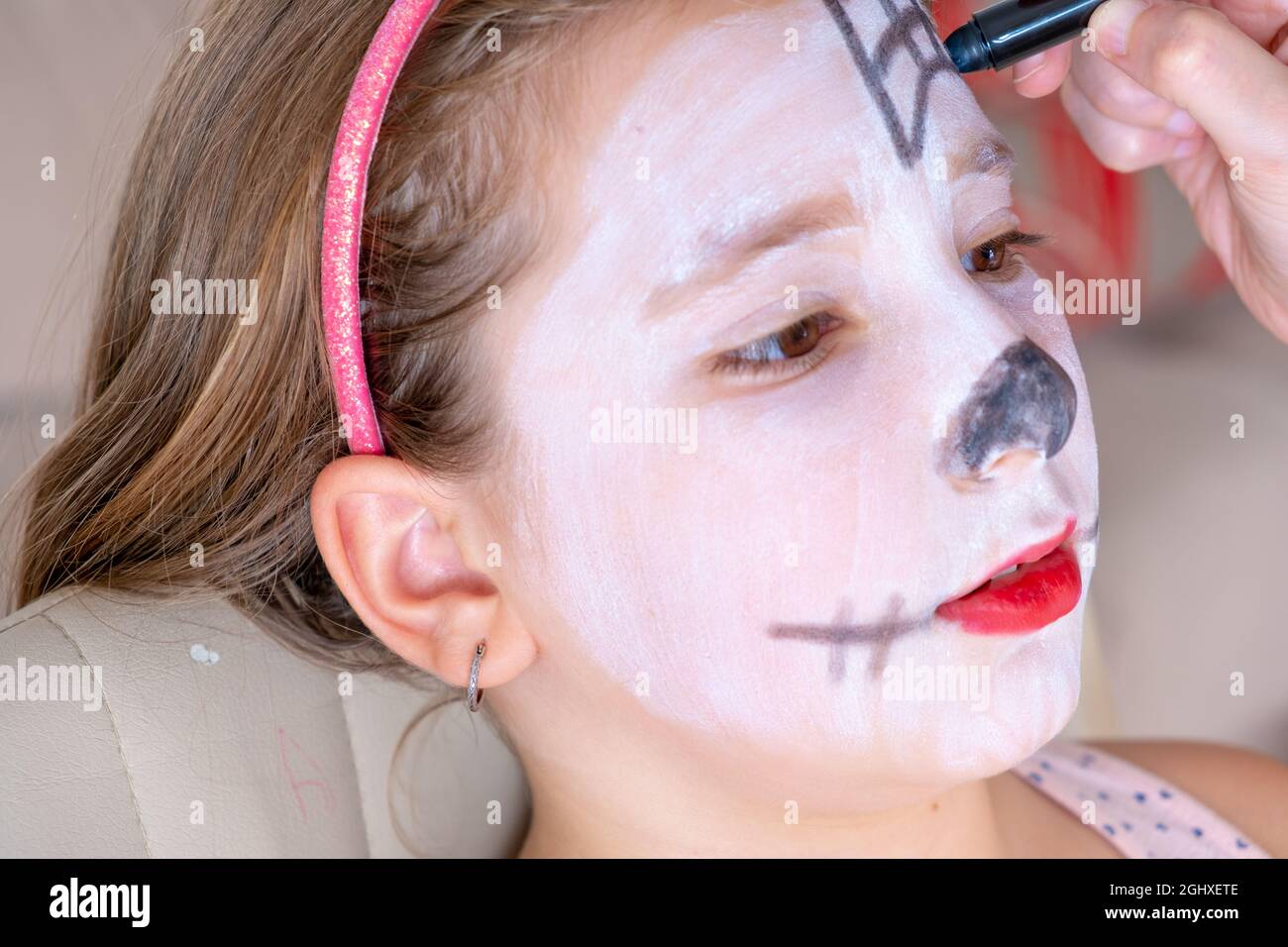 Close-up of the face of a girl who is being made up by her mother ...