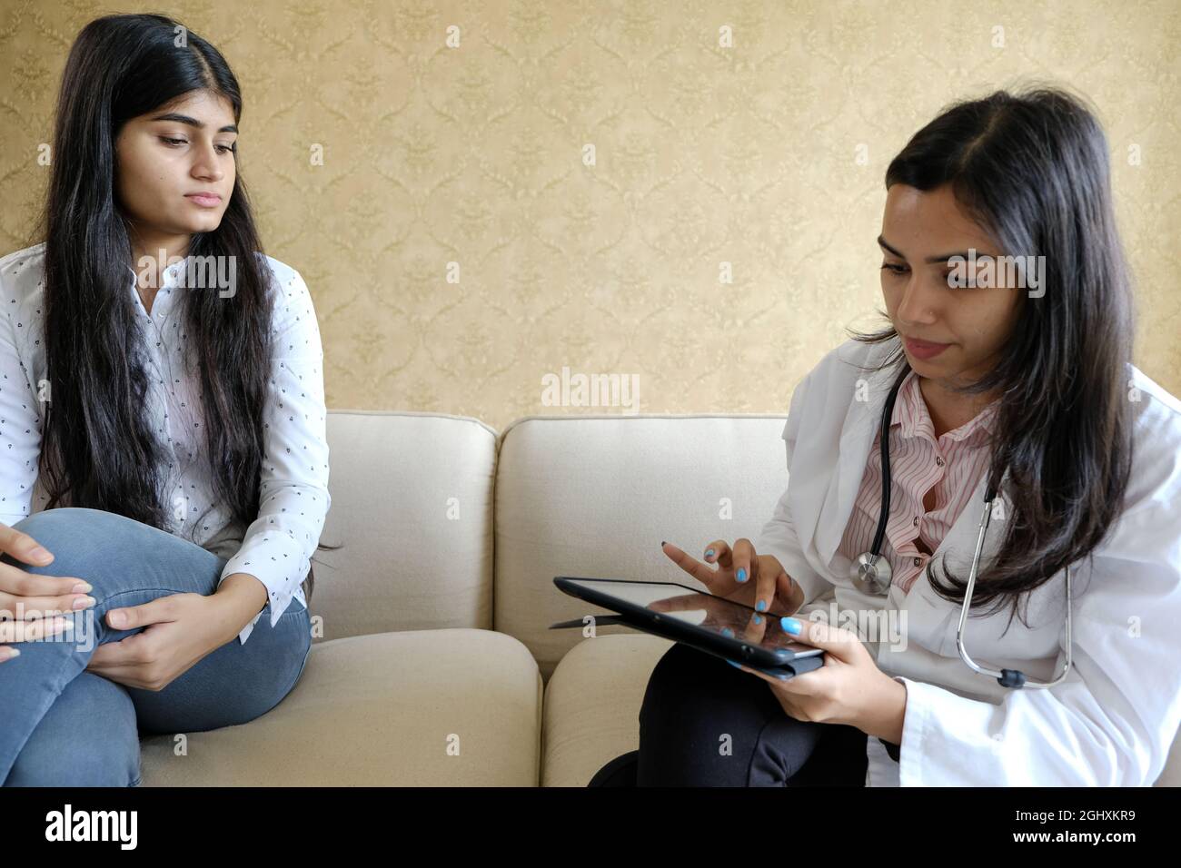 Young Indian females having a discussion while sitting on the sofa at ...