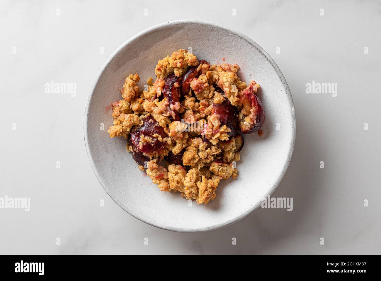 Plum crumble dessert in a plate on white background for tasty breakfast ...