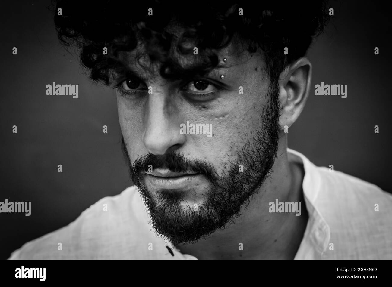 Black and white portrait of a young man with beard and curly hair who ...
