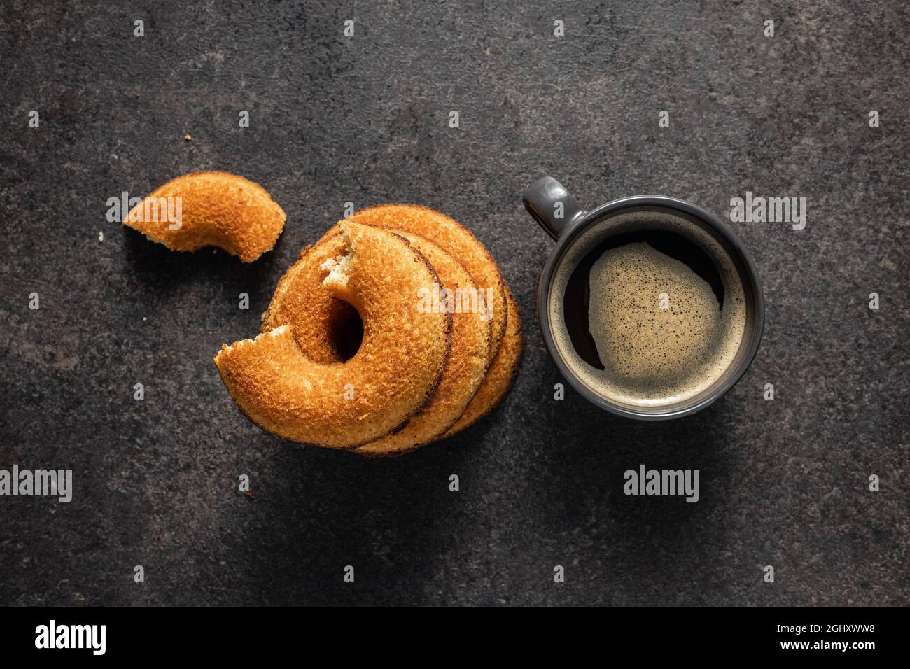 Round sponge cake dessert. Sweet donut with coffee cup on black table ...