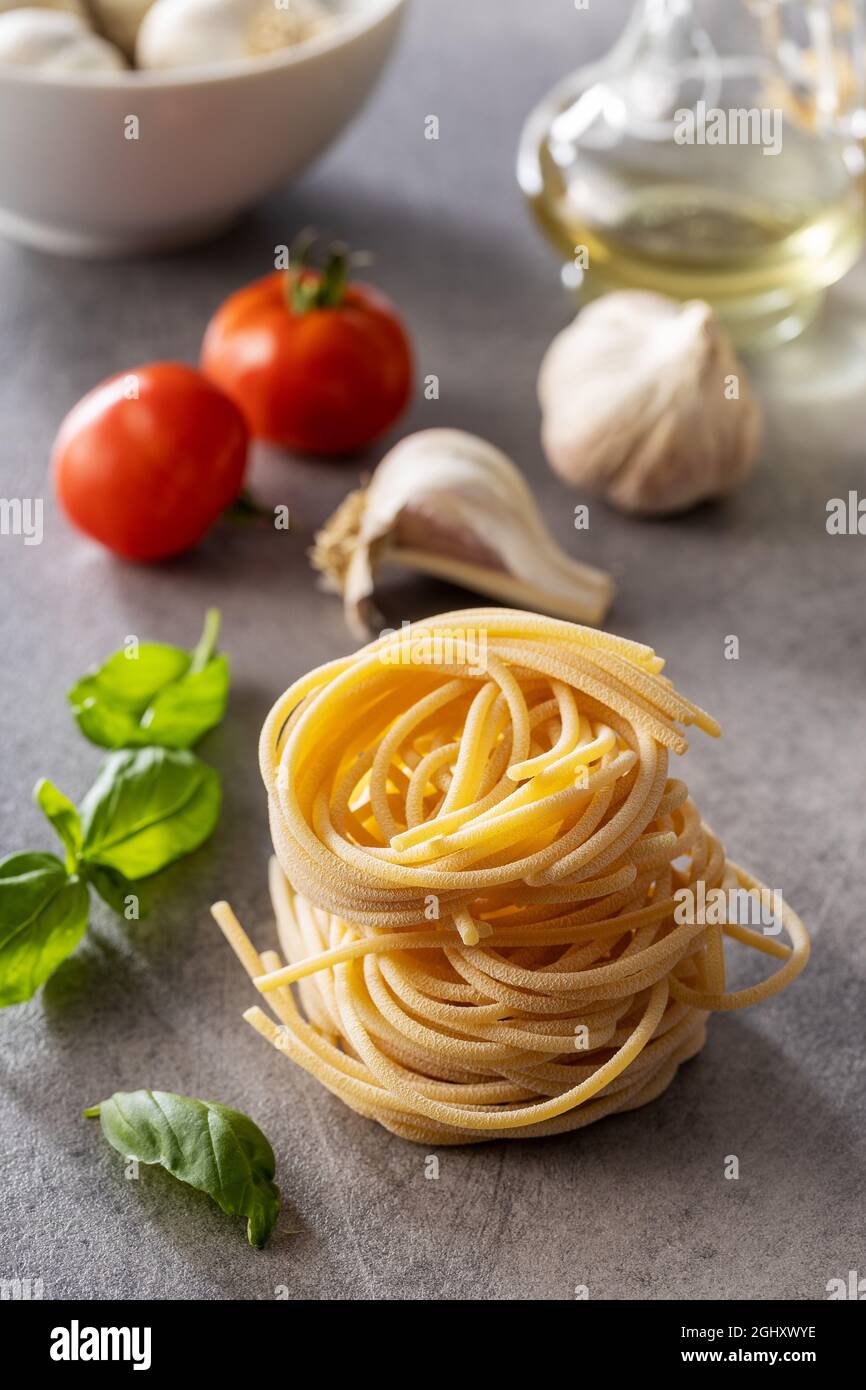 Italian pasta nest, basil, garlic and tomato. Uncooked spaghetti nest ...