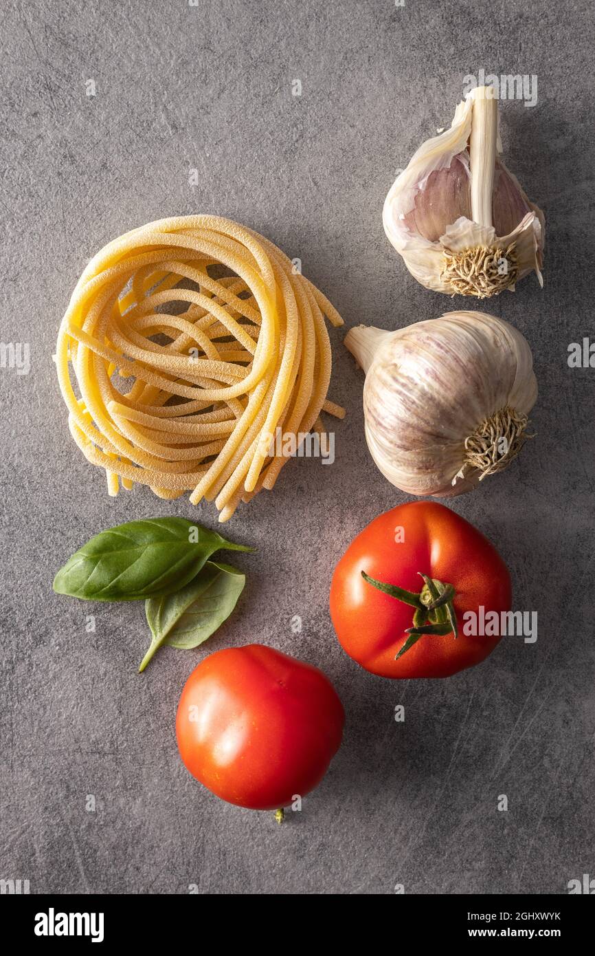 Italian pasta nest, basil, garlic and tomato. Uncooked spaghetti nest ...