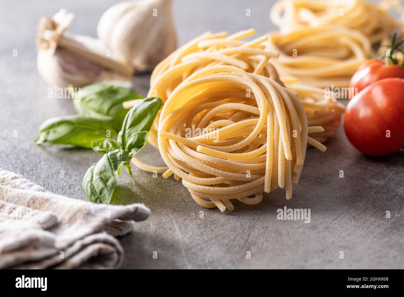 Italian pasta nest, basil, garlic and tomato. Uncooked spaghetti nest ...