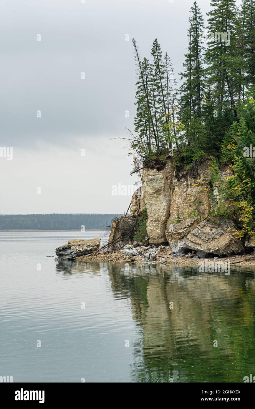 wooded river bank with crumbling marble cliffs, water erosion of ...