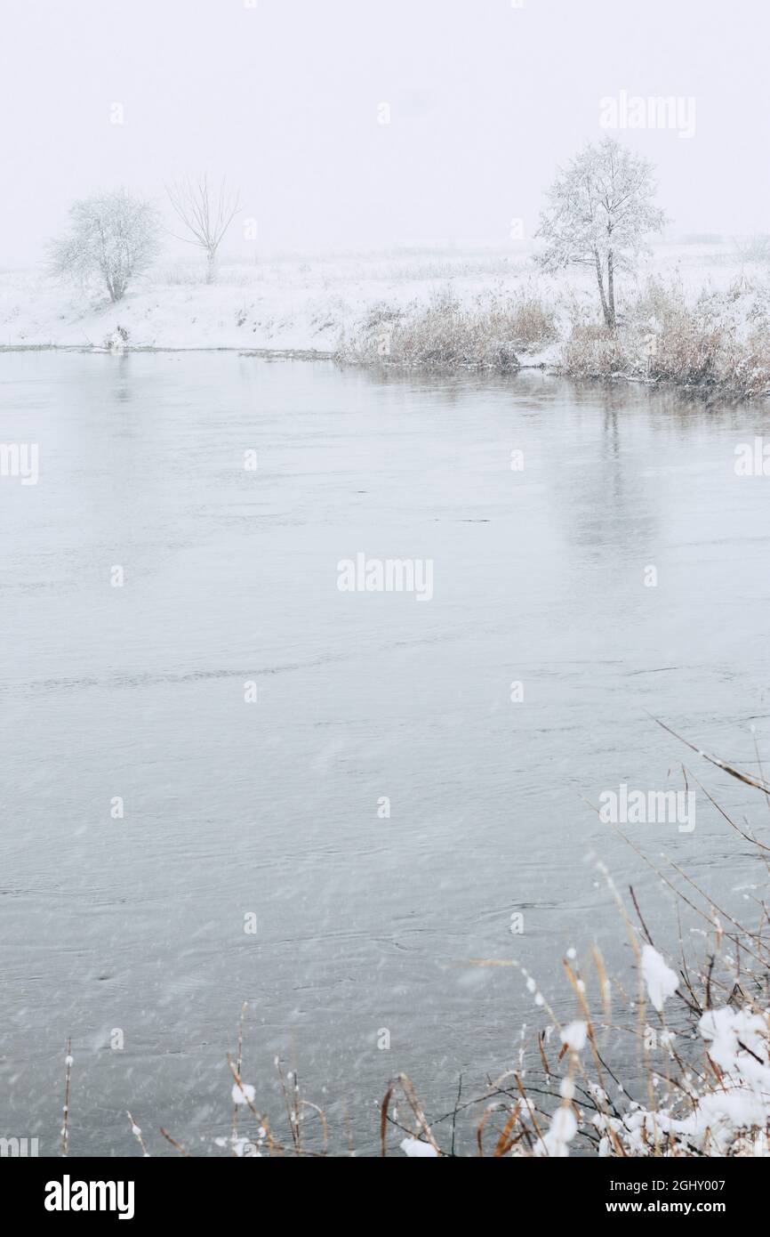 River in winter during snowfall in january with bank covered in snow ...