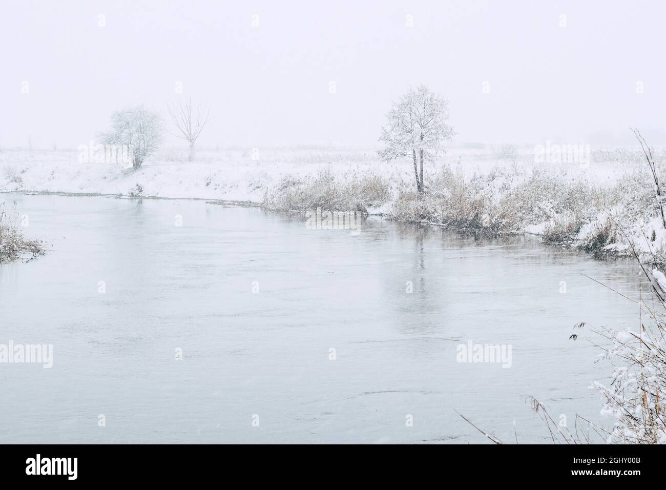 River in winter during snowfall in january with bank covered in snow ...