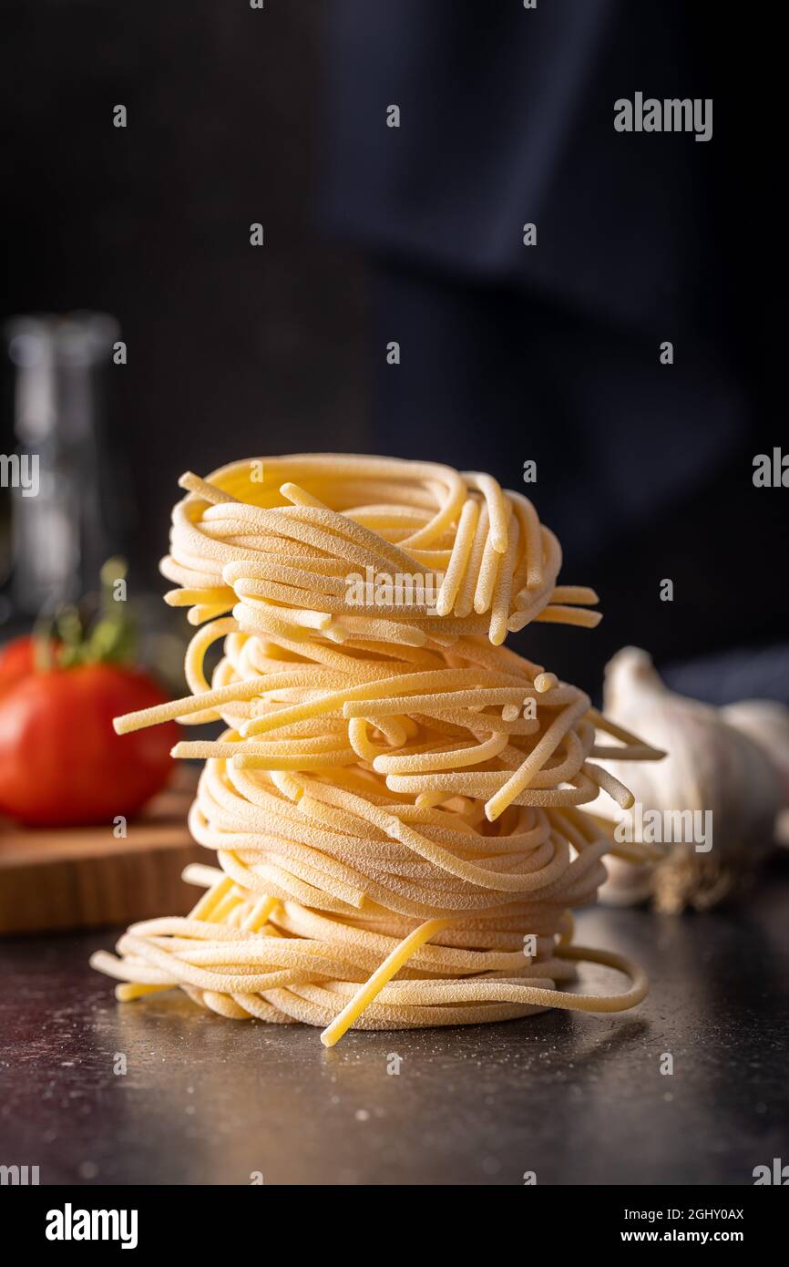Italian pasta nest. Uncooked spaghetti nest on black table Stock Photo ...