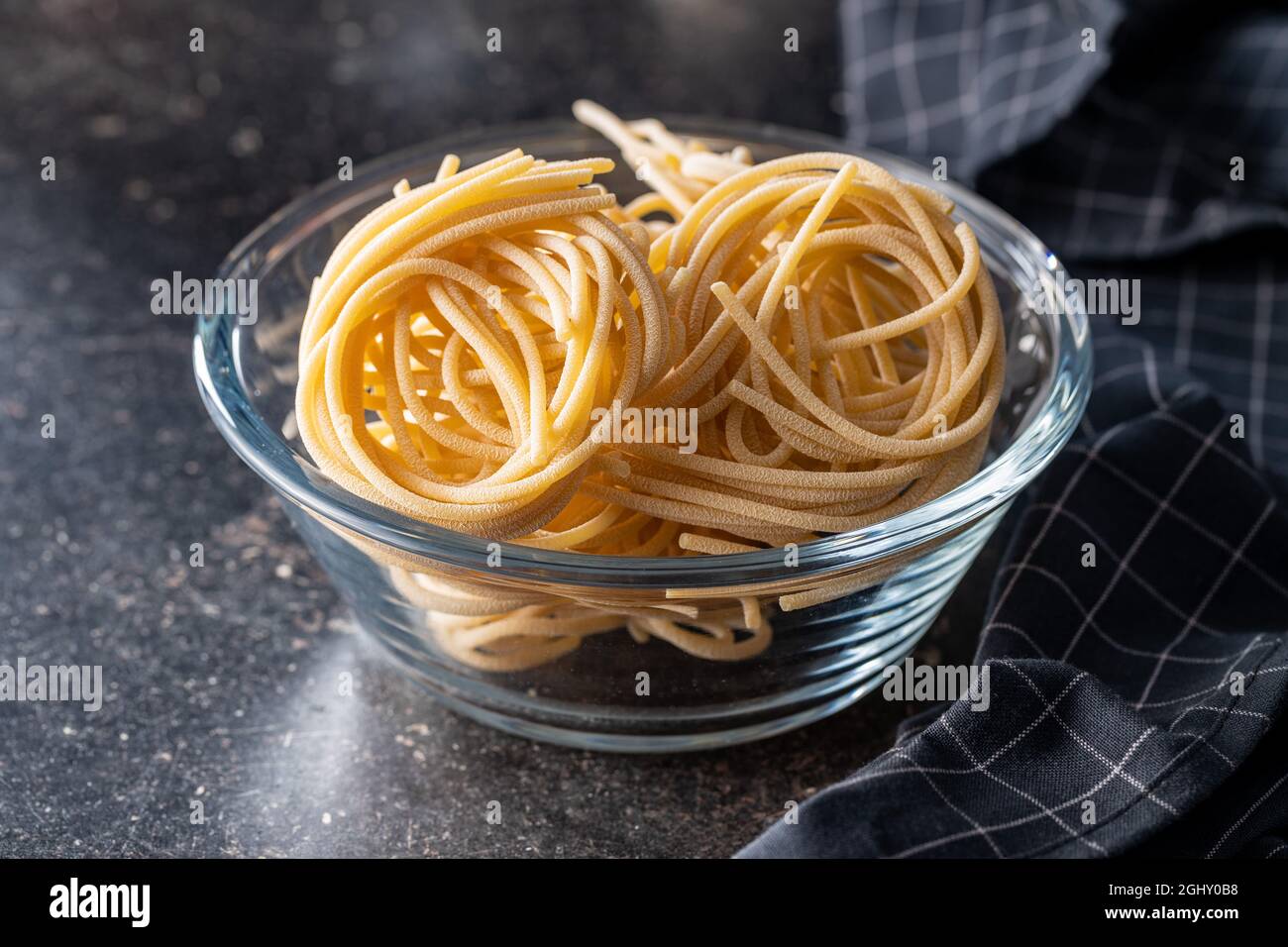 Italian pasta nest. Uncooked spaghetti nest in bowl on black table ...