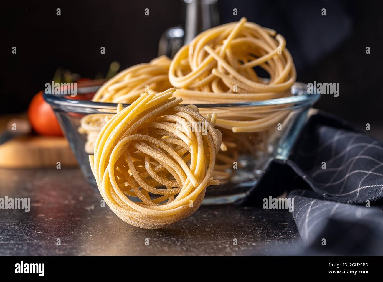 Italian pasta nest. Uncooked spaghetti nest in bowl on black table ...