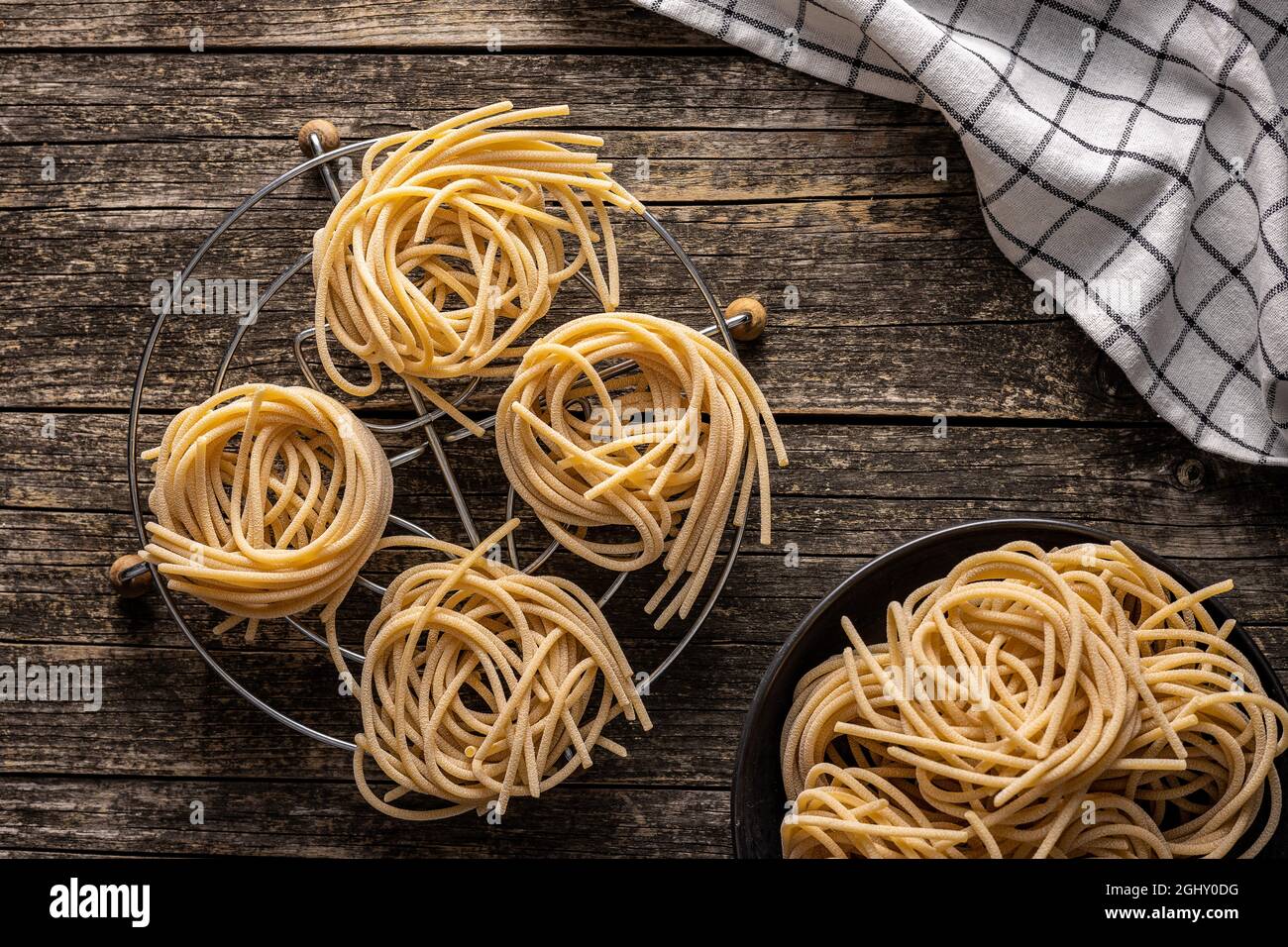 Italian pasta nest. Uncooked spaghetti nest on old wooden table. Top ...
