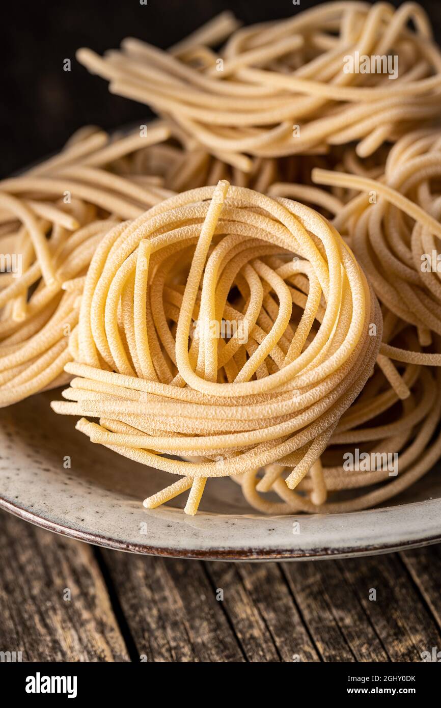 Italian pasta nest. Uncooked spaghetti nest on a plate Stock Photo - Alamy