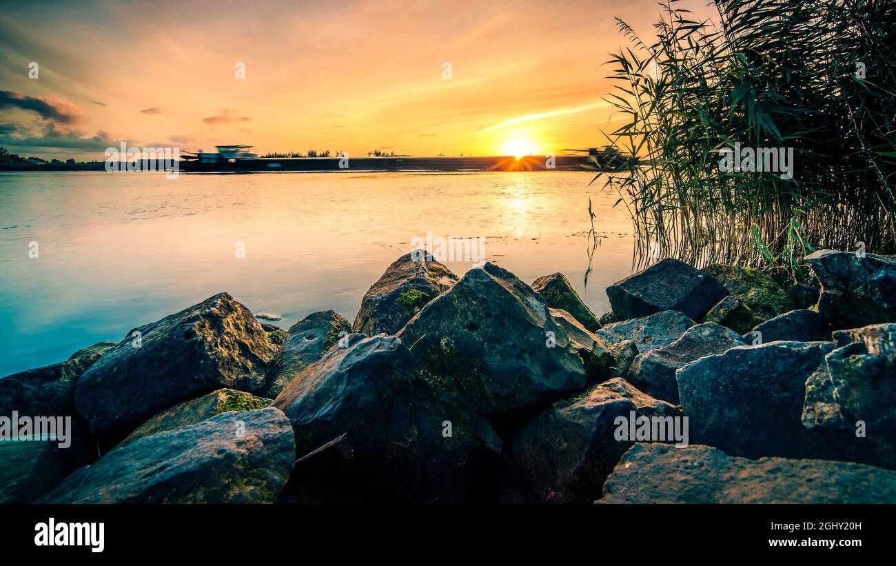 Landscape of the IJssel river surrounded by rocks during the sunset in ...