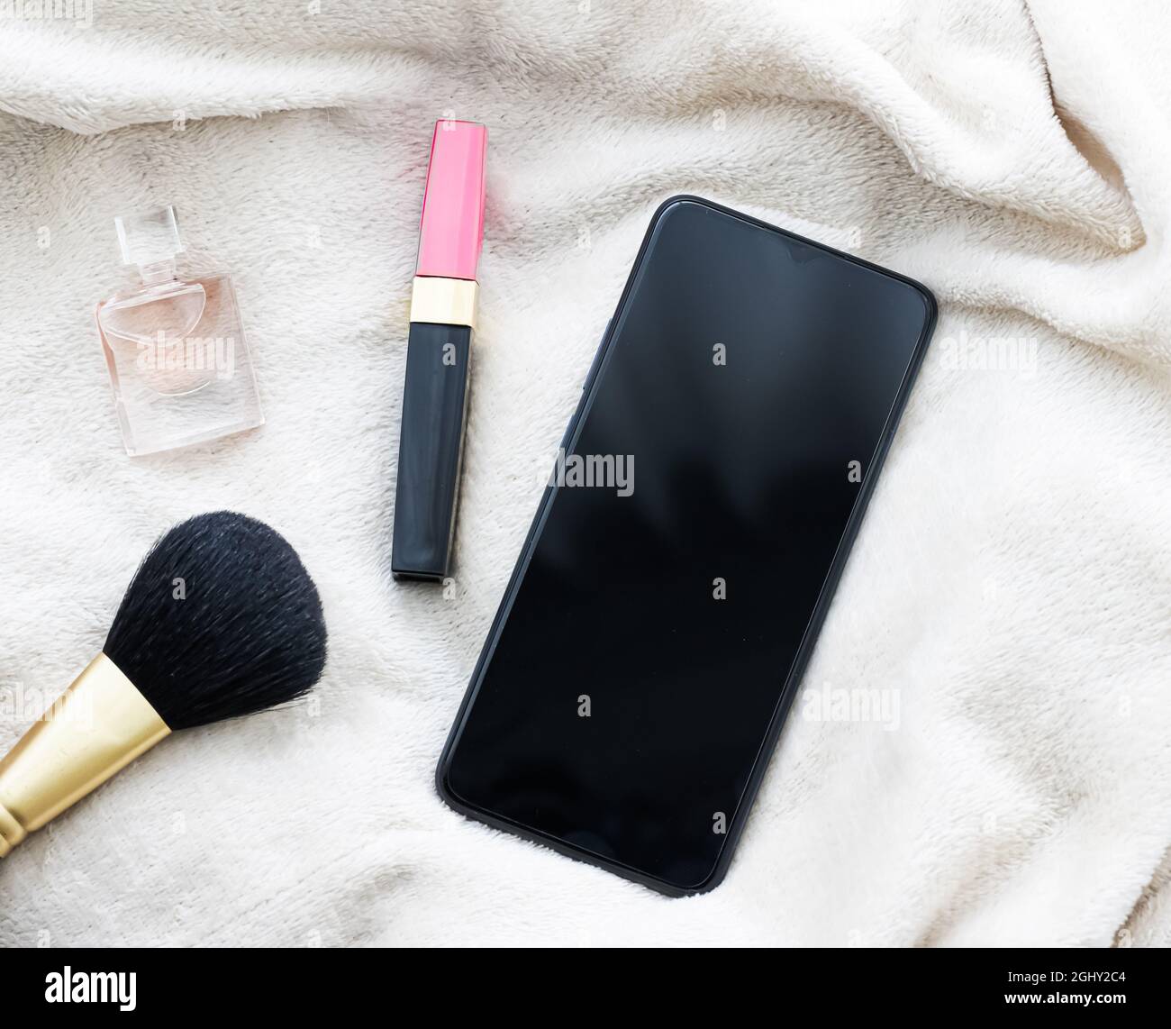 Girly flatlay with mobile phone, lipstick, perfume and make-up brush ...