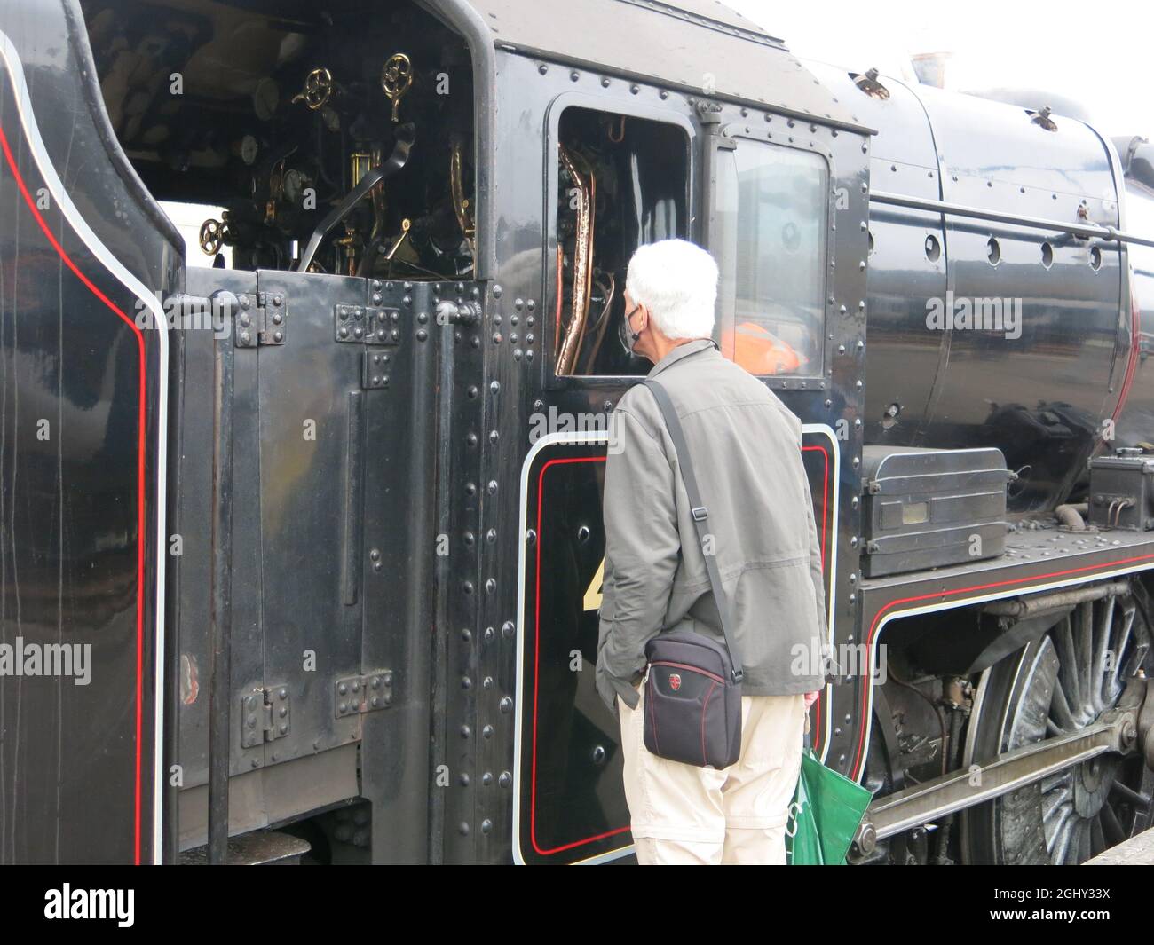 A male passenger / steam train enthusiast looks in to the engine cab of ...