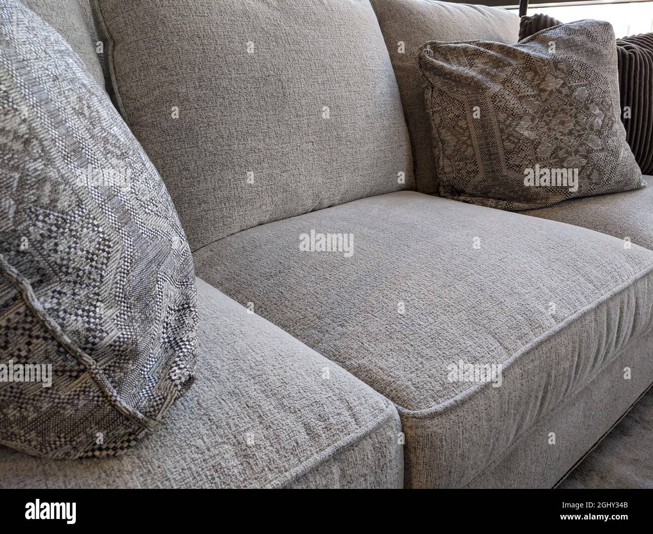 Close up view of several pillows piled on a light colored couch in a ...