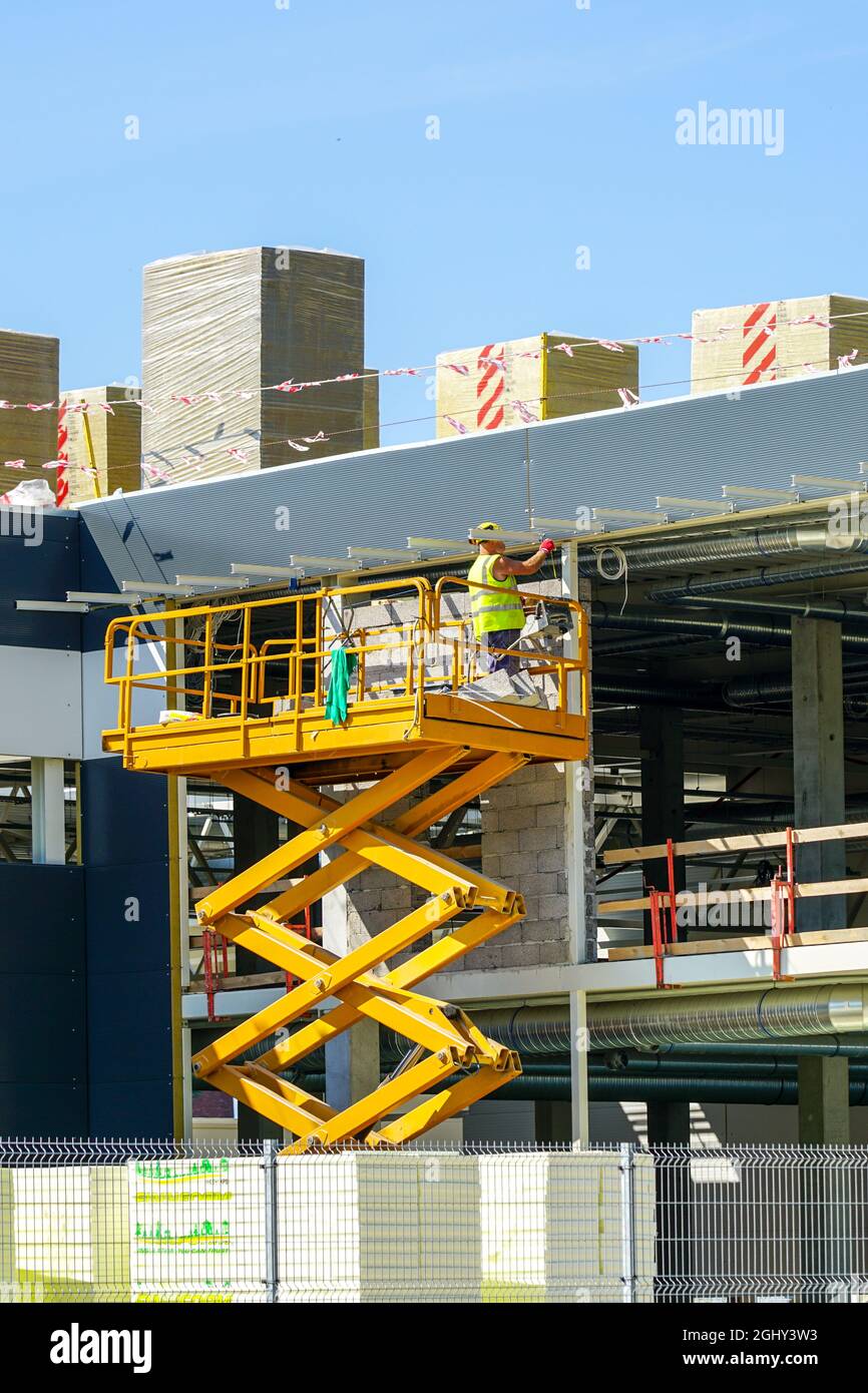 yellow scissor lift on the background of a new factory metal frame ...
