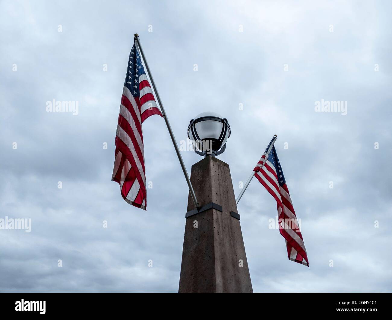 Low angle view of two American flags attached to a lamp post against a ...