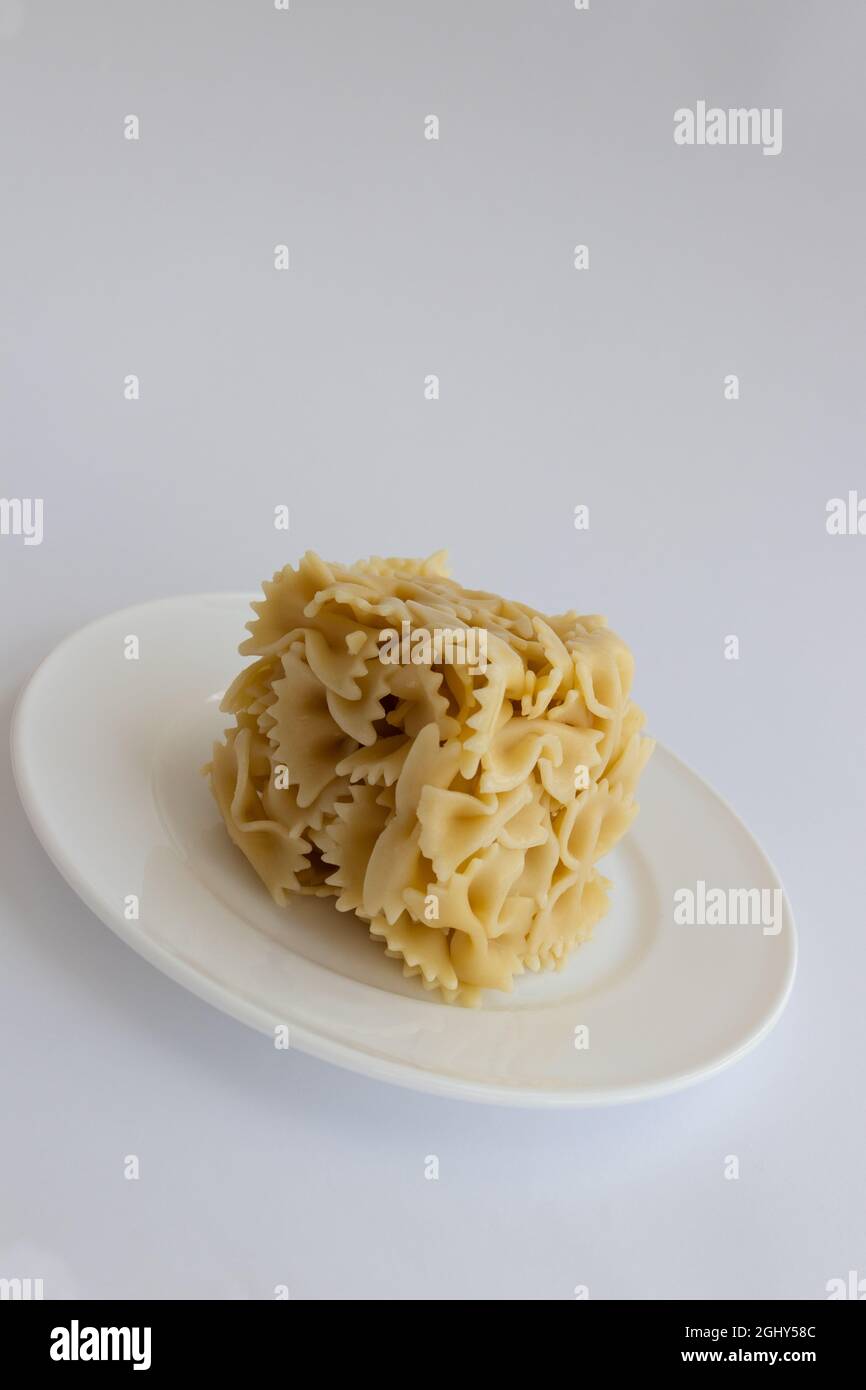 Cooked farfallini pasta in a shape of cube on a white plate Stock Photo ...
