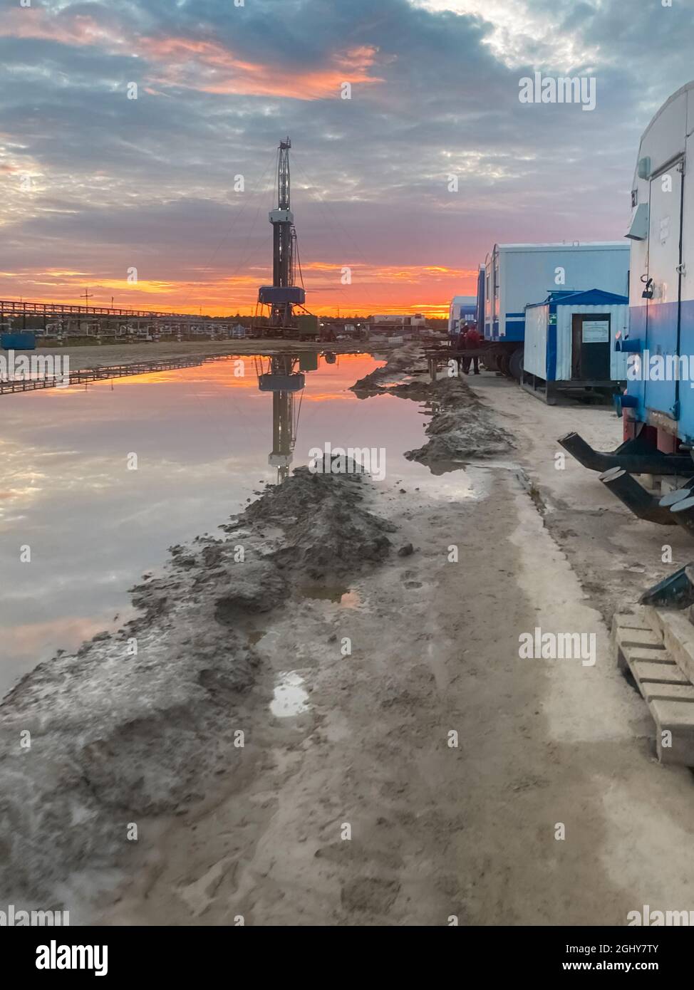 An oil field with an oil rig and wagons. Reflection in a puddle at ...