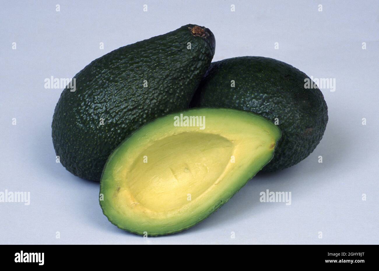 STUDIO IMAGE OF WHOLE AND A HALVED AVOCADO (PERSEA AMERICANA) ALSO ...