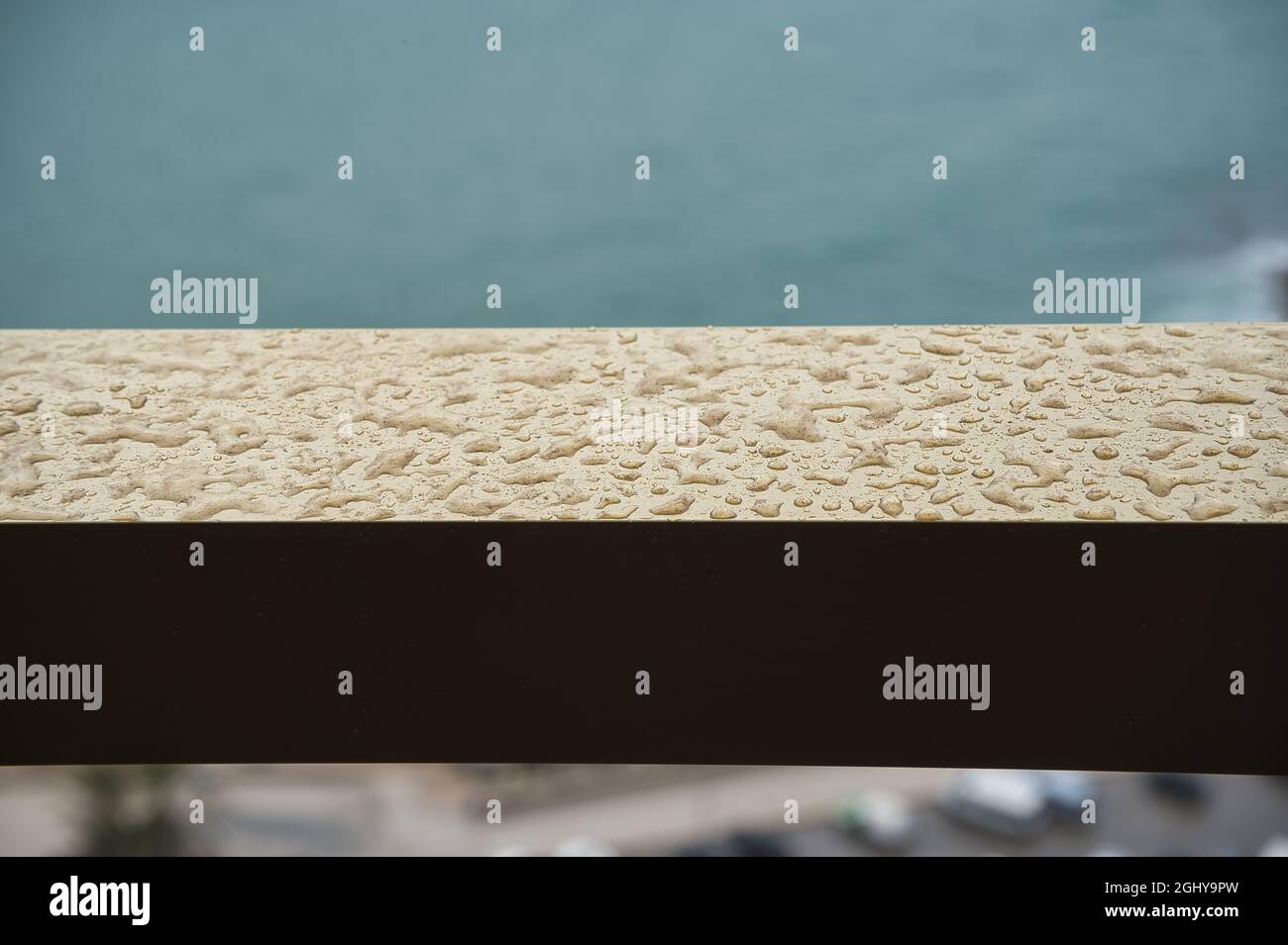 raindrops on golden balcony railing with defocused sea background. view ...