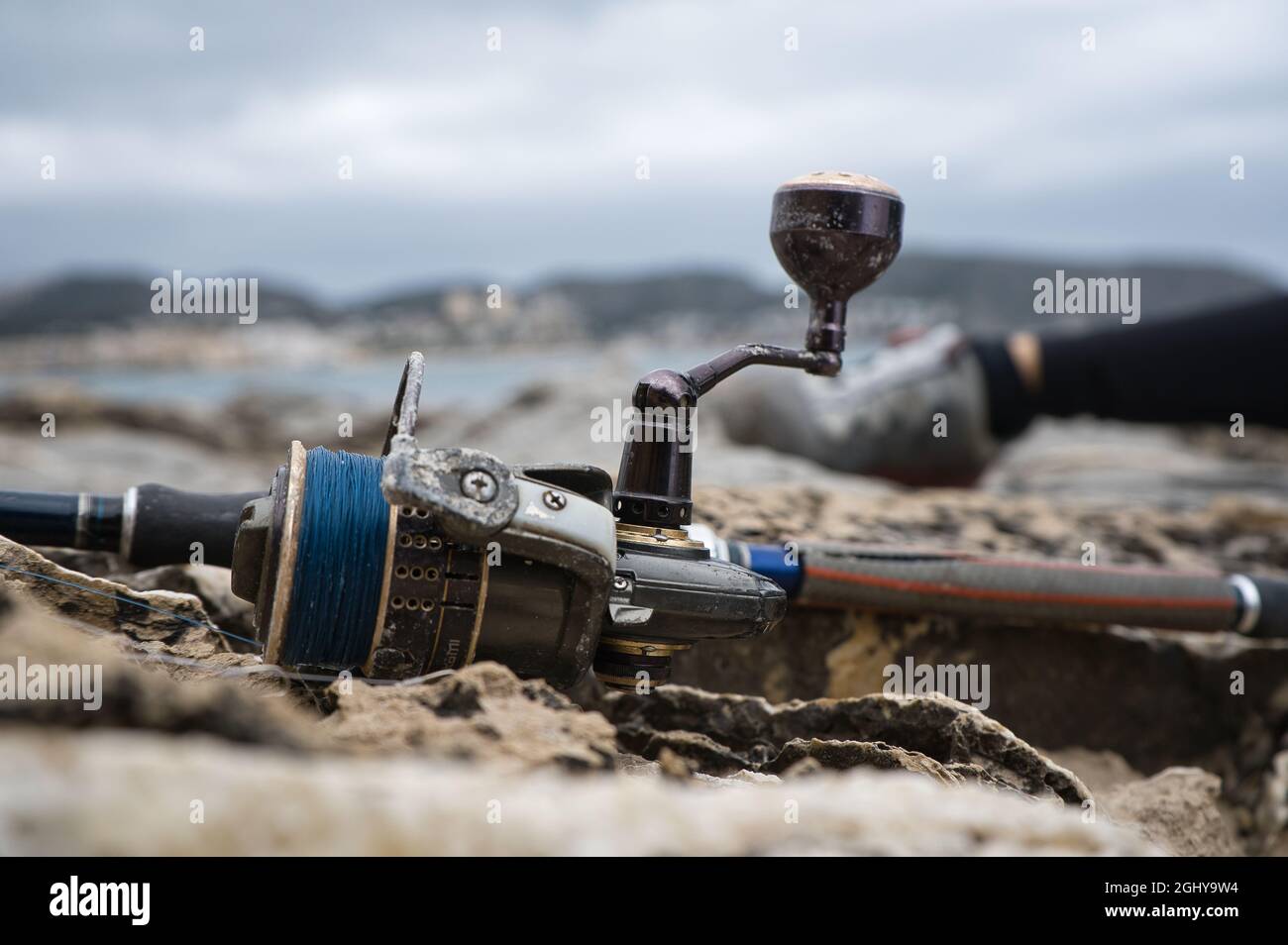 fishing rod with foot with trekking shoe on the rocks with unfocused ...