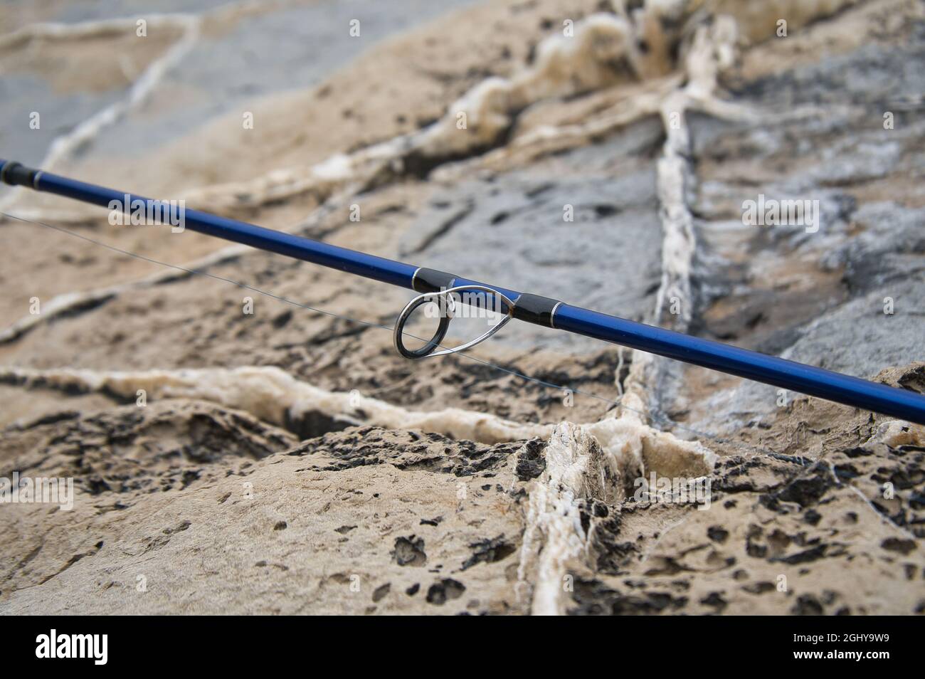 detail of fishing rod on the rocks. portrait Stock Photo - Alamy