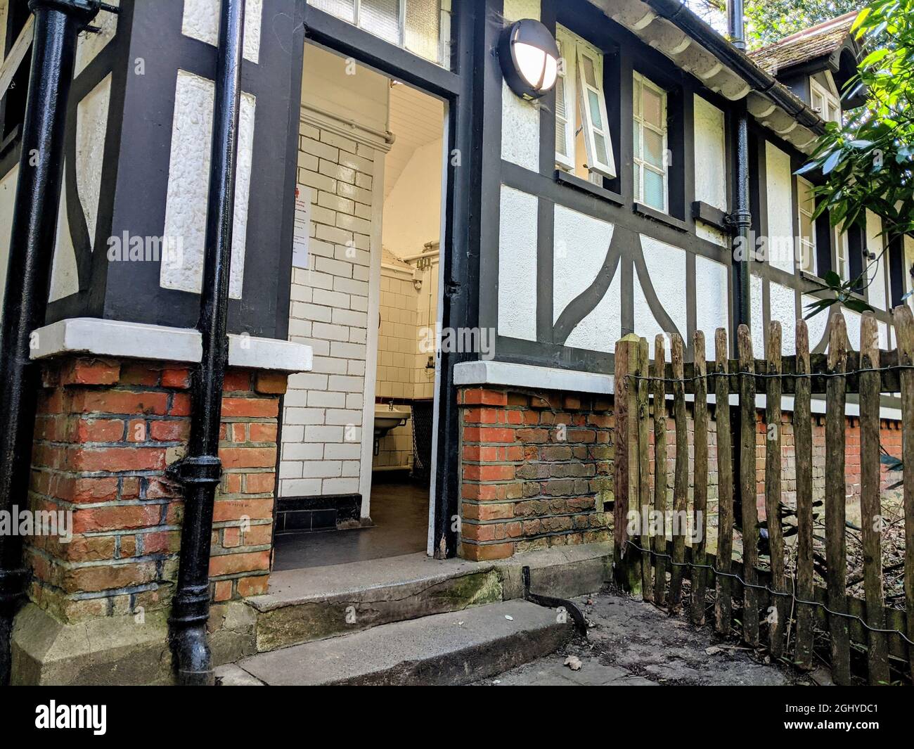 Entrance to public toilet with black white facade, wooden fences and ...
