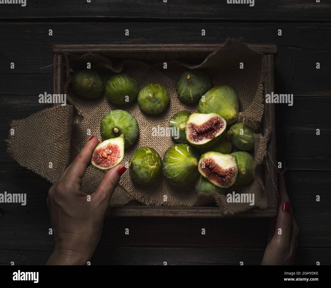 Person grabbing a fresh fig from a box on a rustic background Stock ...