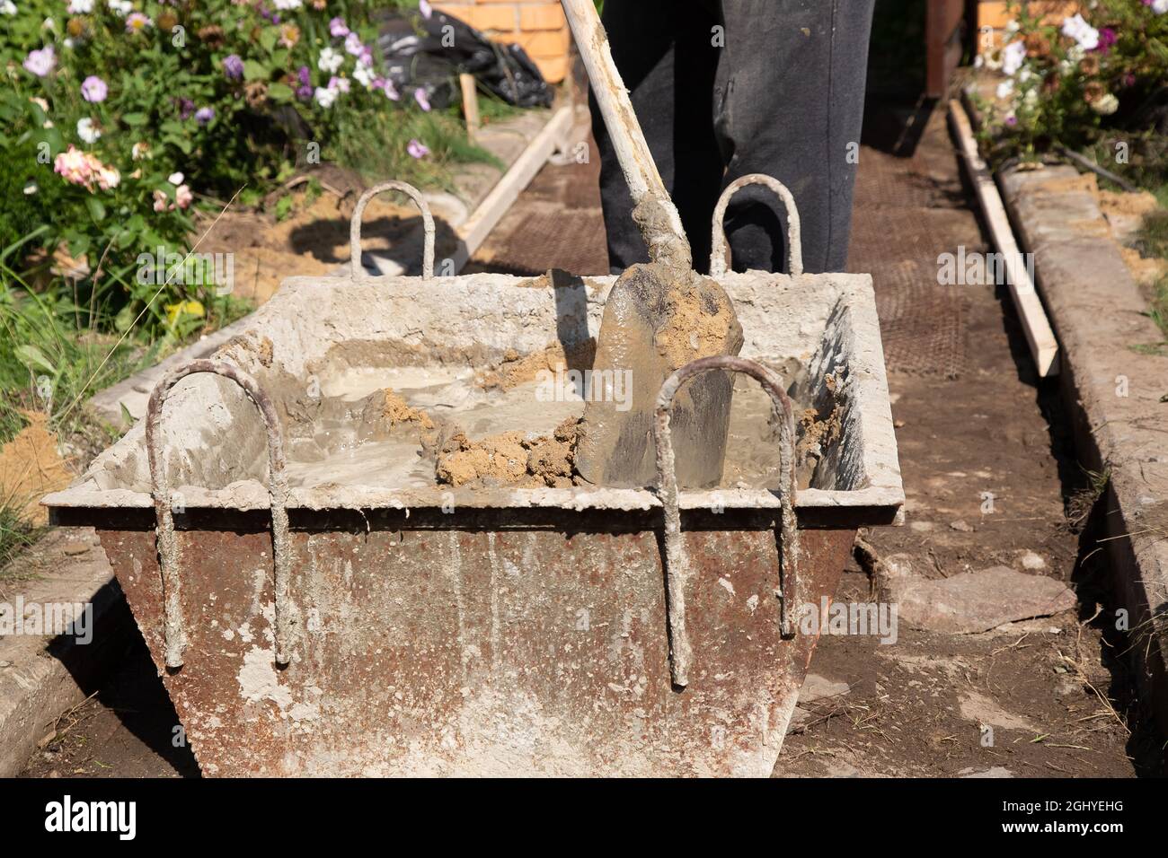 A man unloads sand into a cement mixture for pouring a garden path ...