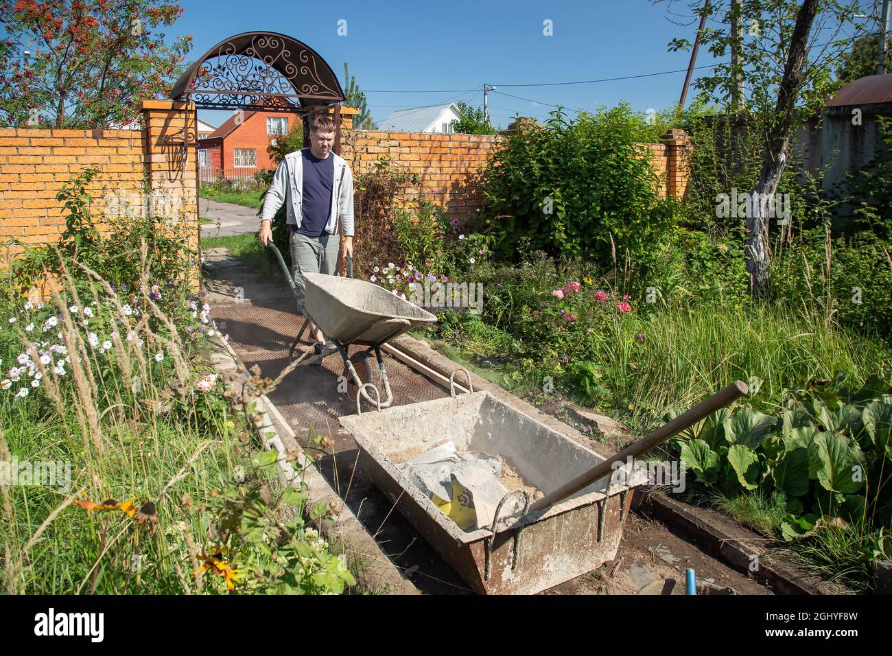 A man unloads sand into a cement mixture for pouring a garden path ...