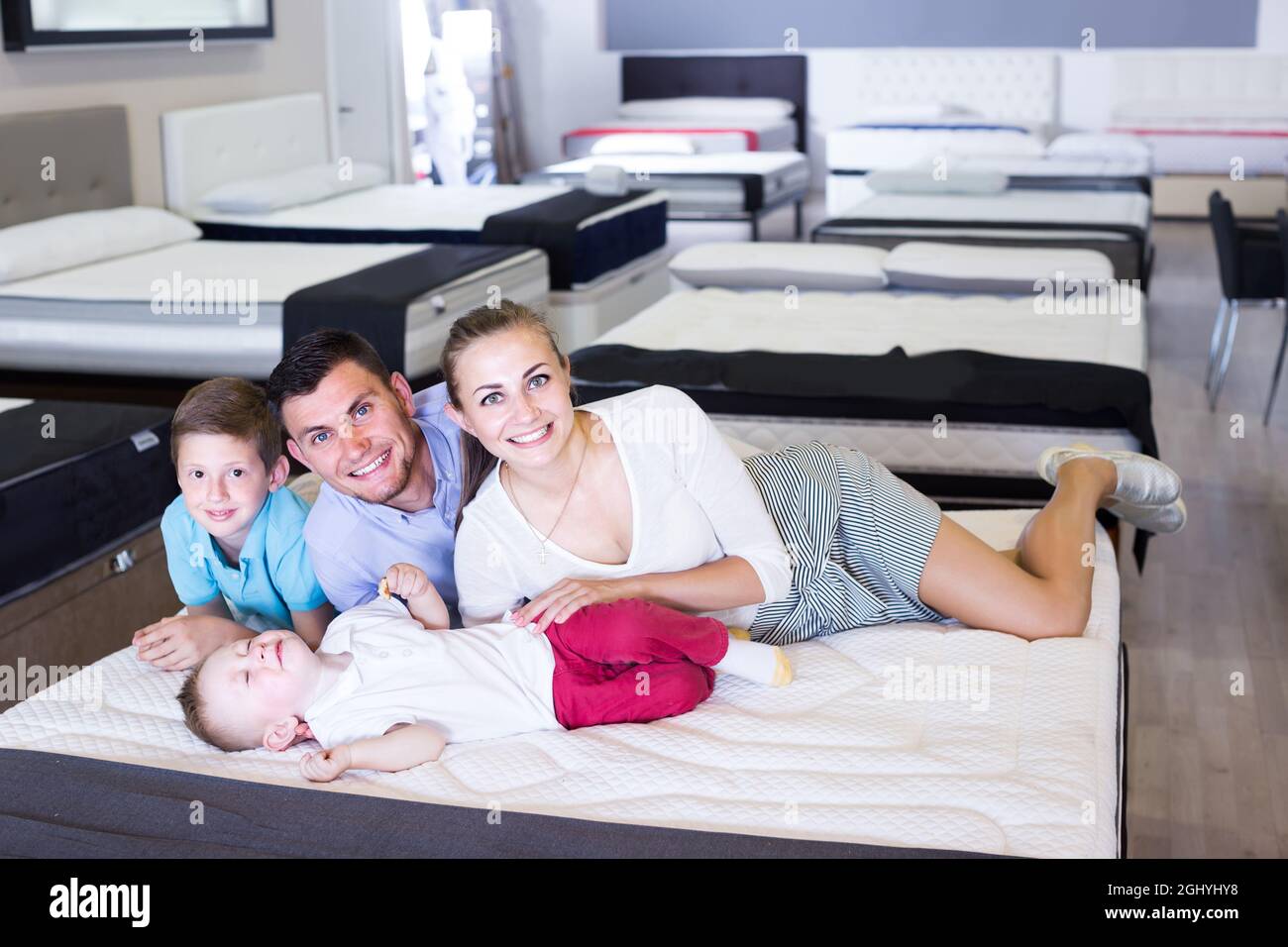 parents with two young sons testing mattress in store Stock Photo - Alamy