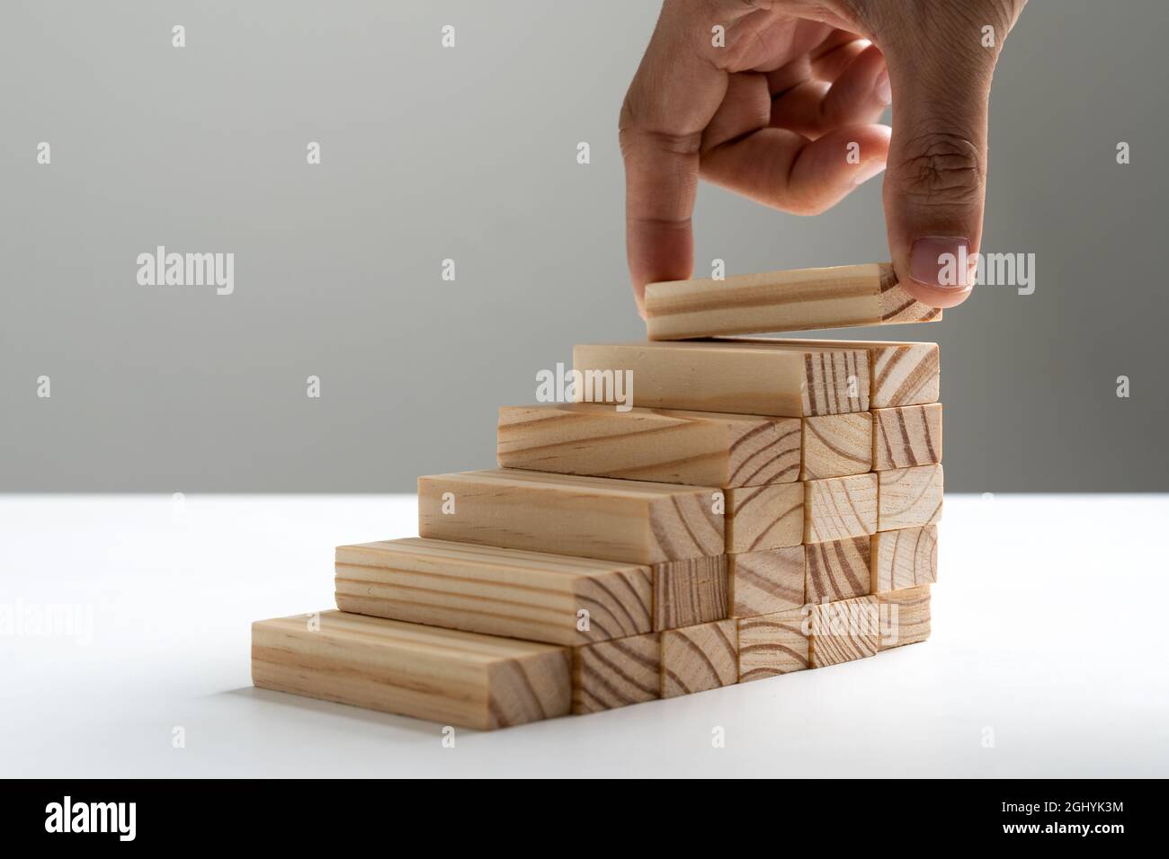 Hand arranging wood block stacking as step stair Stock Photo - Alamy