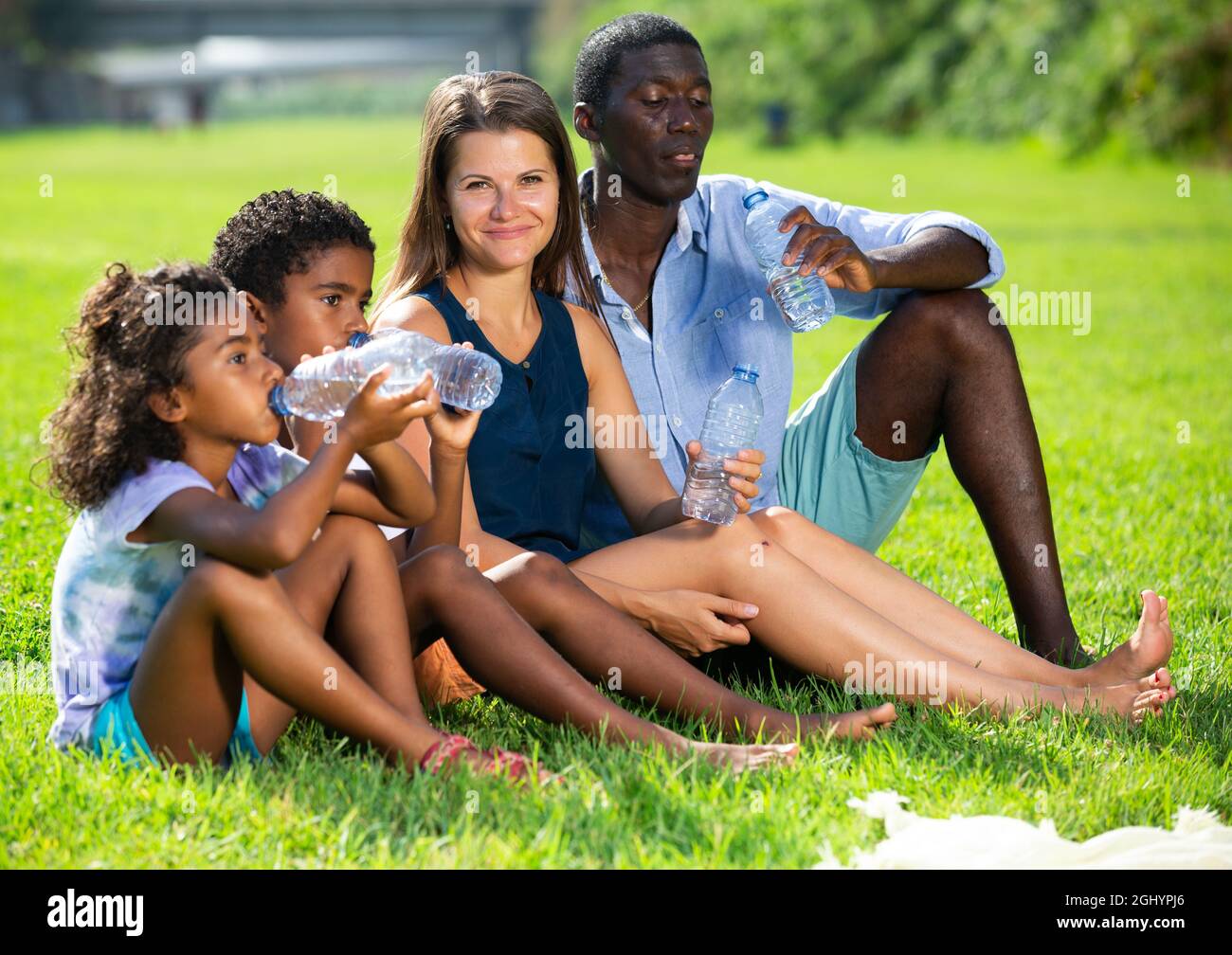 Family drinking water sitting on grass Stock Photo - Alamy